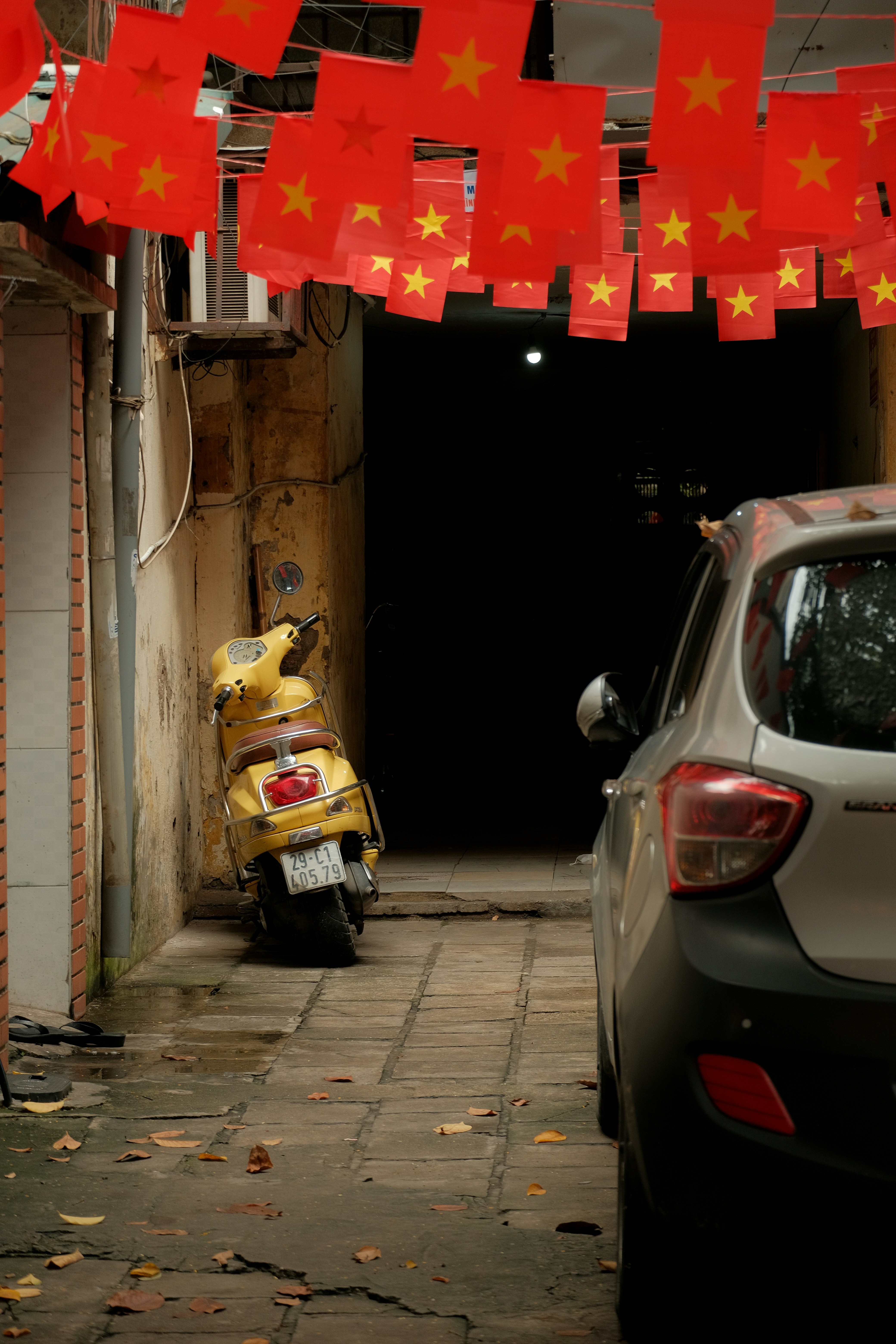 Yellow scooter and car in alley with flags