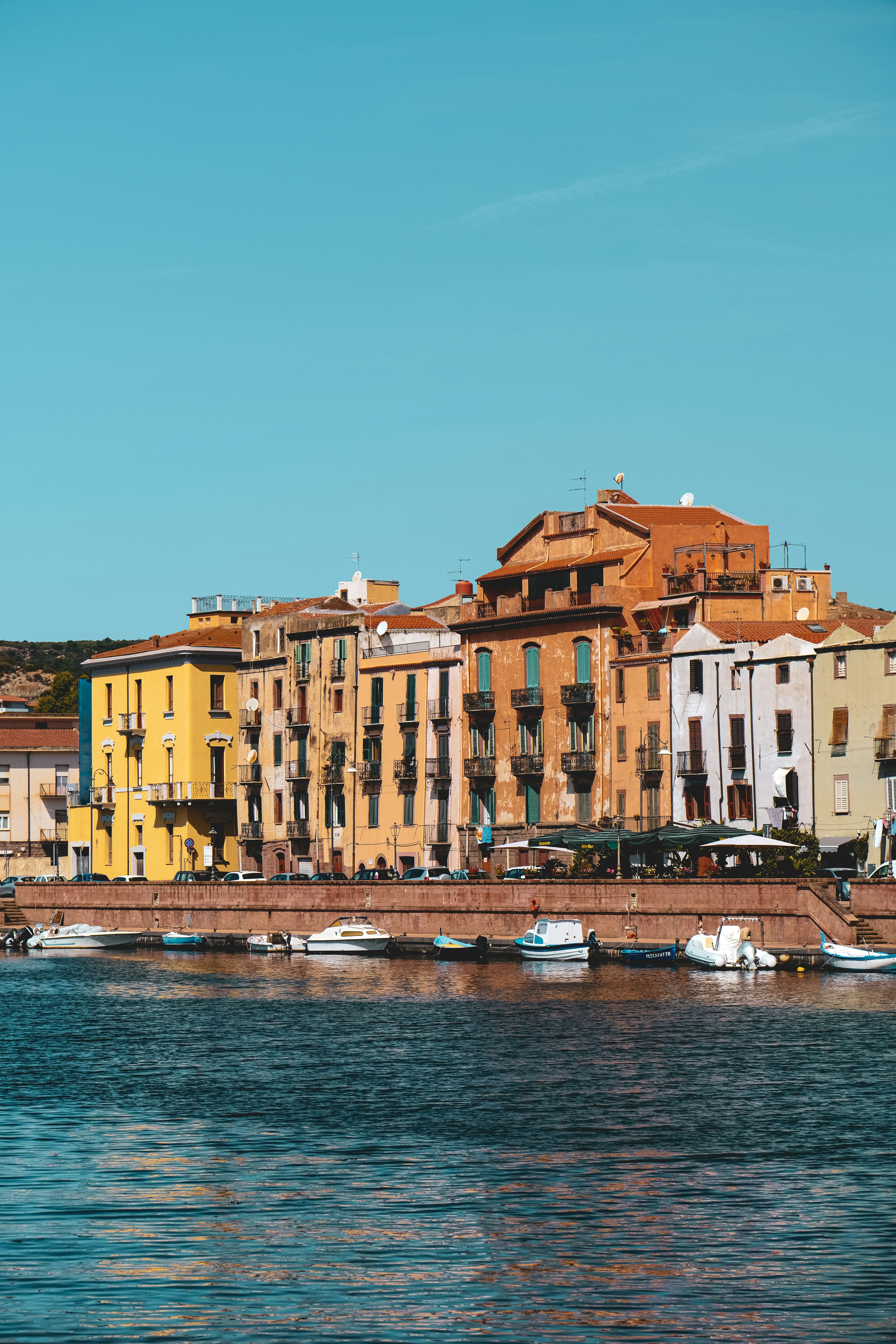 Vibrant waterfront buildings reflect in calm waters, showcasing a blend of architectural styles. The scene captures the essence of coastal living.