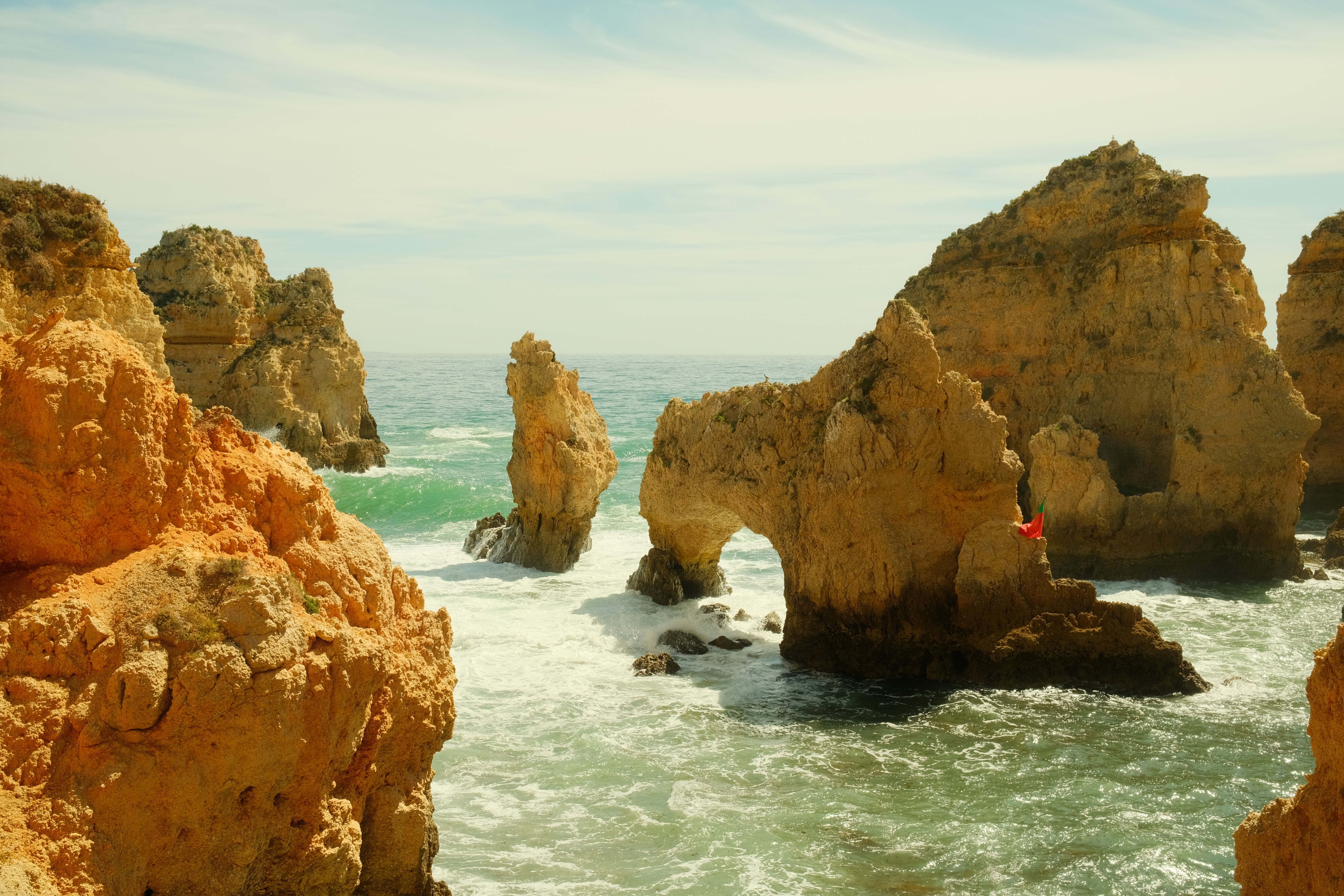 Jagged rock formations in the ocean under a blue sky.