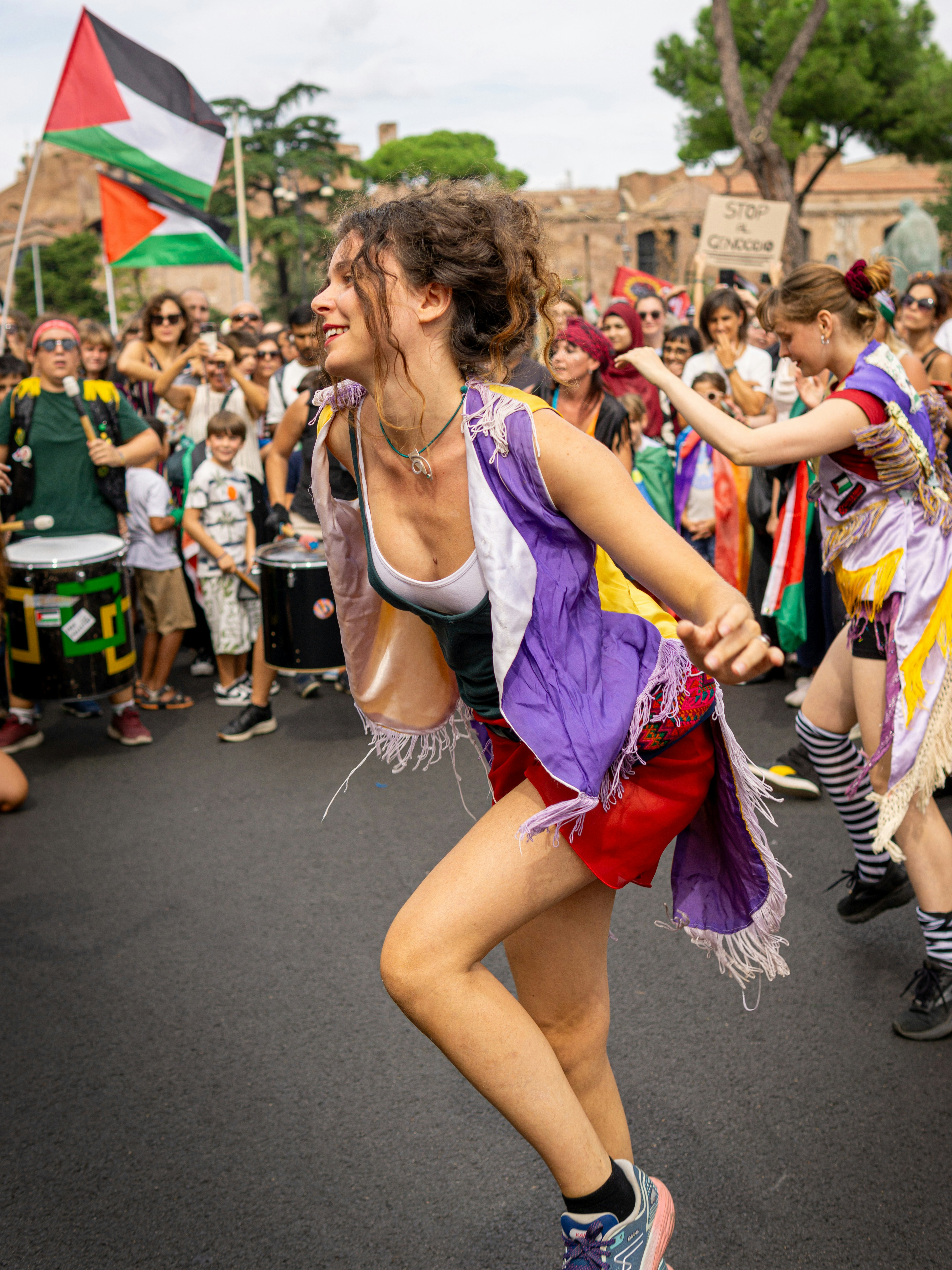 A lively street dance performance amidst a vibrant crowd, showcasing diverse expressions of joy and solidarity. Colorful flags and costumes enhance the festive atmosphere.