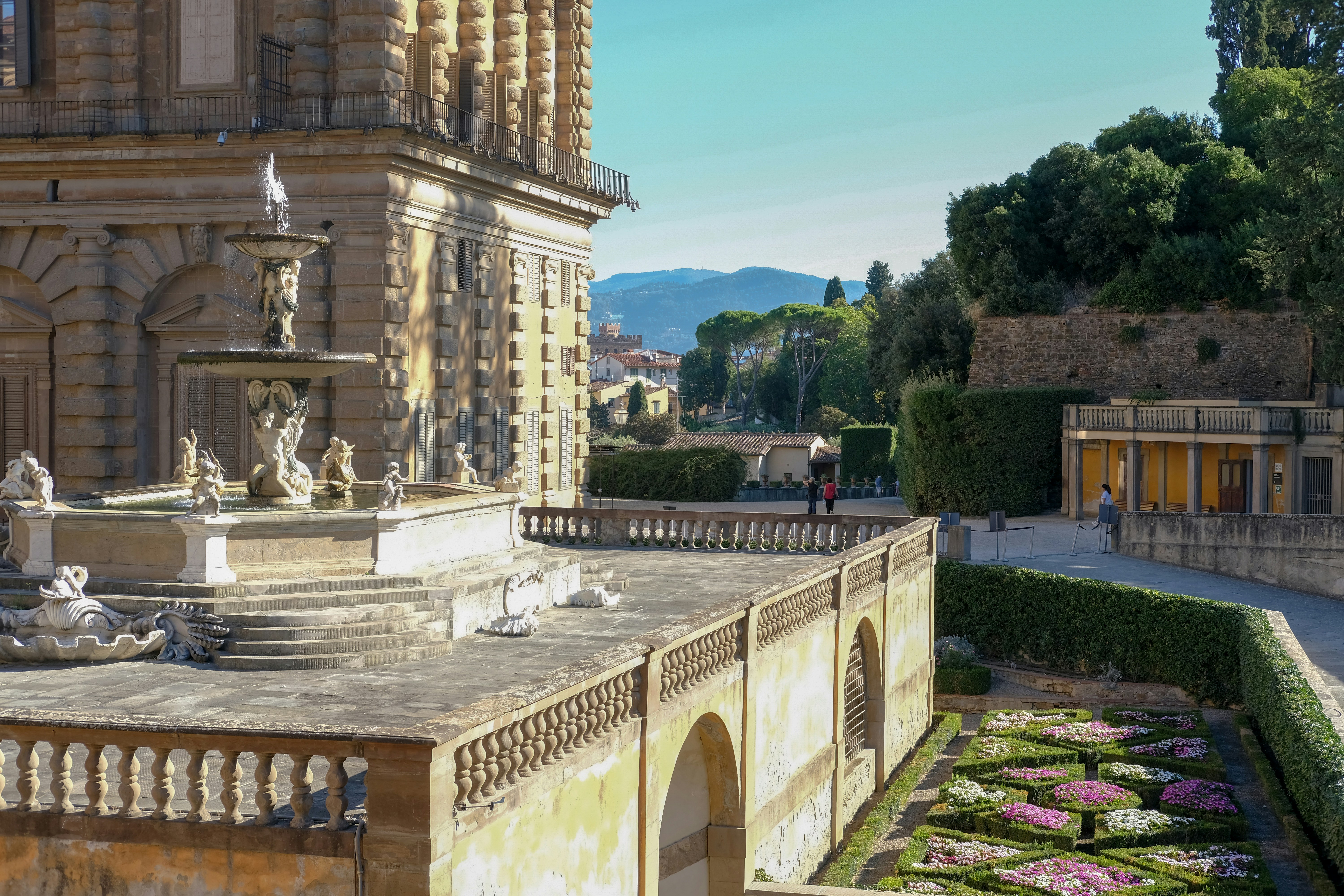 Ornate fountain and formal gardens beside historic building