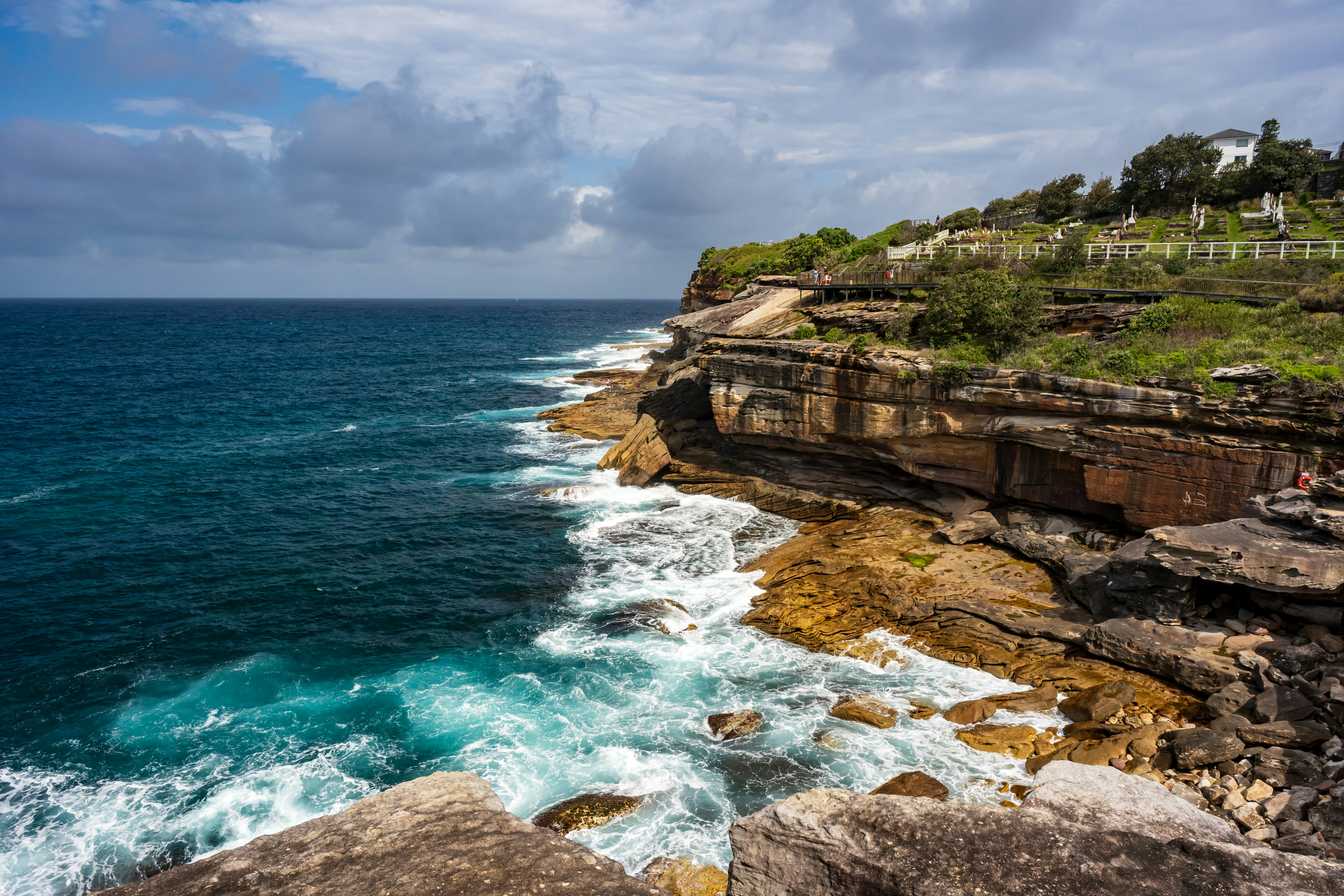 Dynamic waves crashing against rugged cliffs under a moody sky, highlighting the coastal landscape's natural beauty.