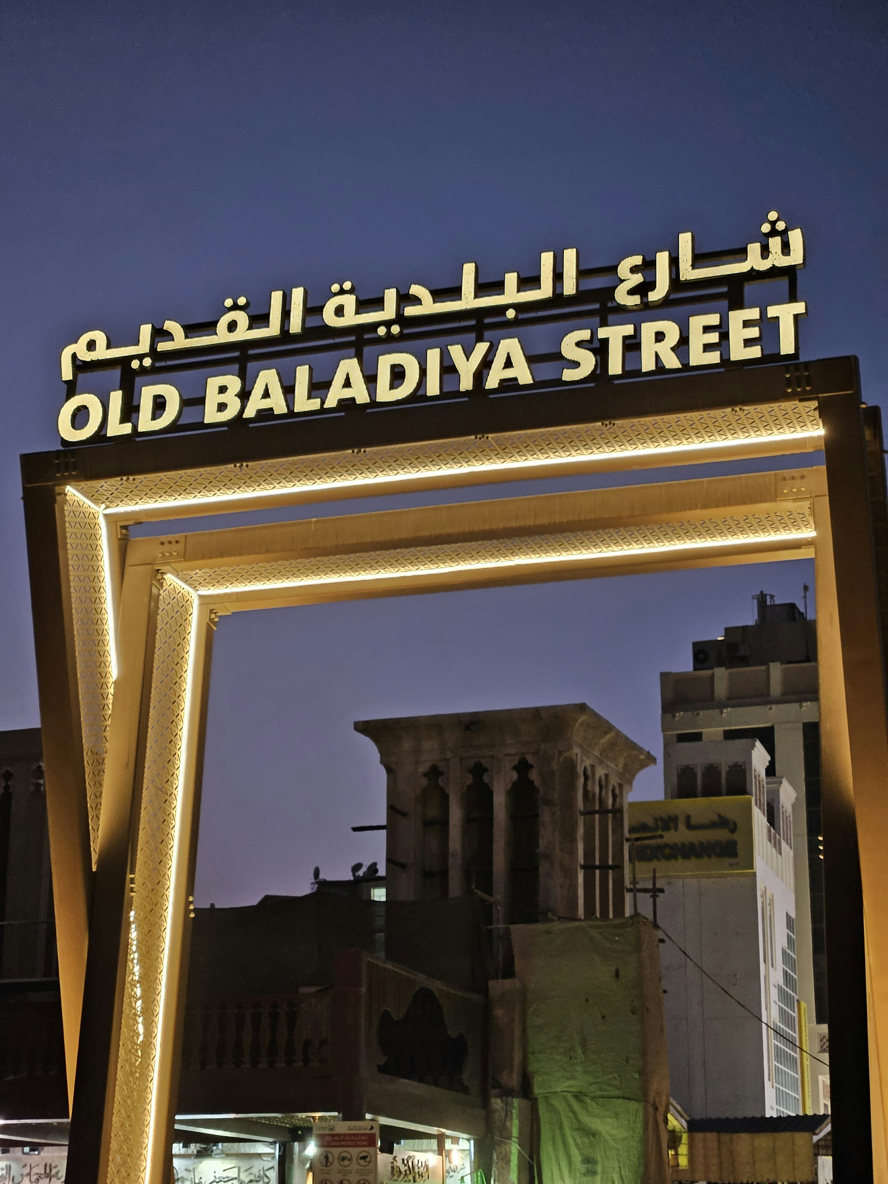 Gateway to Old Baladiya: Neon-Illuminated Frame Over a Night Street