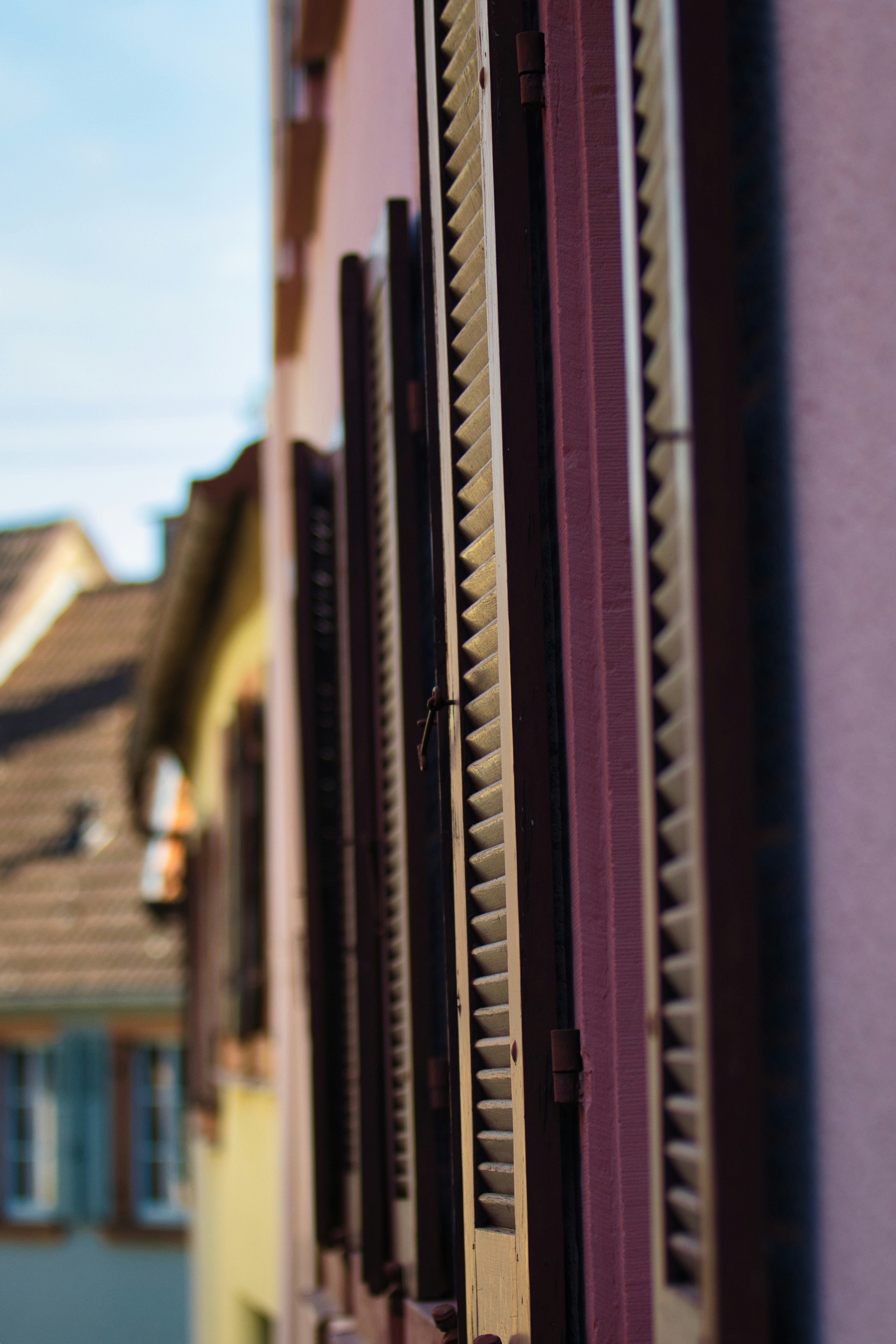 Row of open window shutters on a pink building.