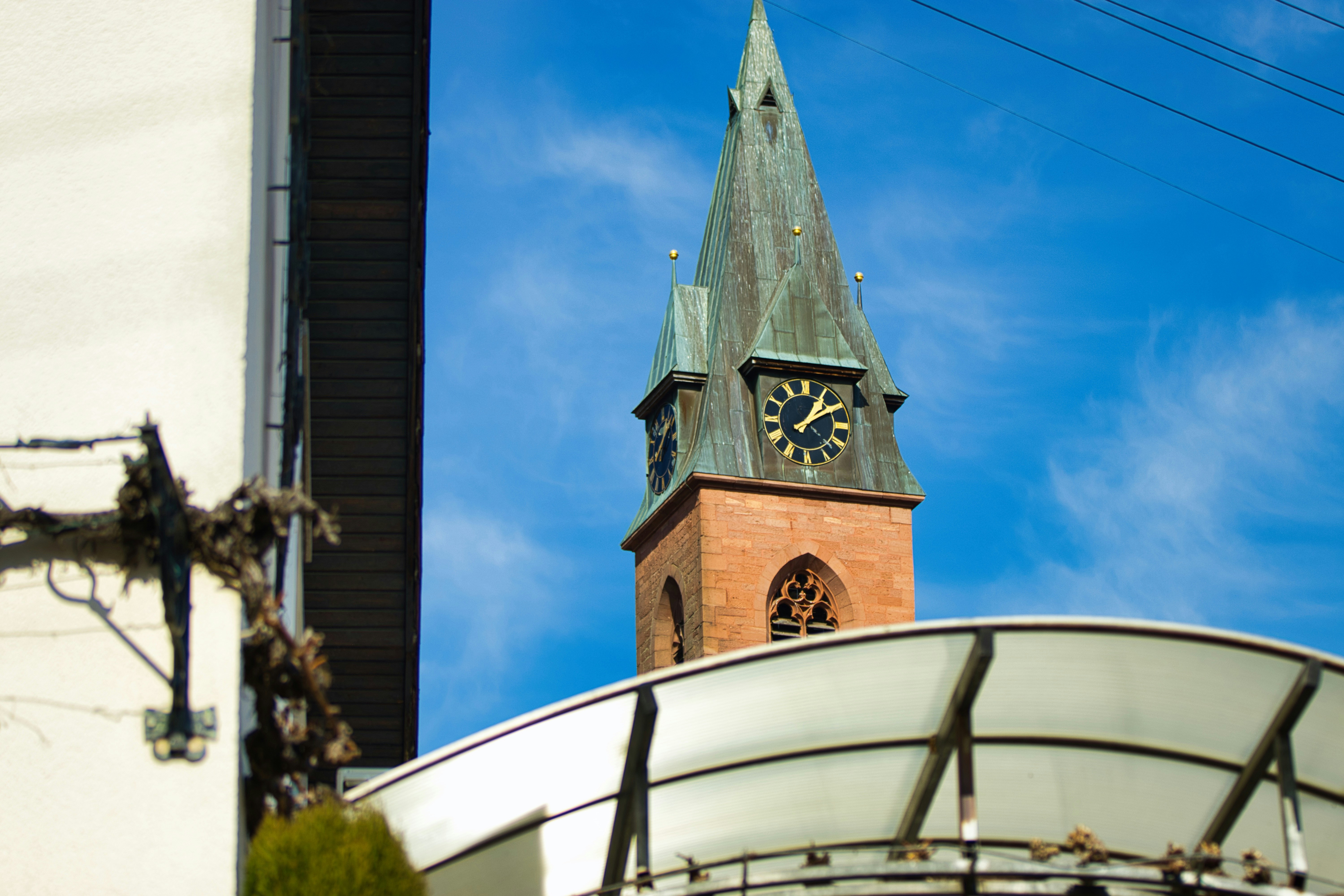 Brick church tower with clock against blue sky