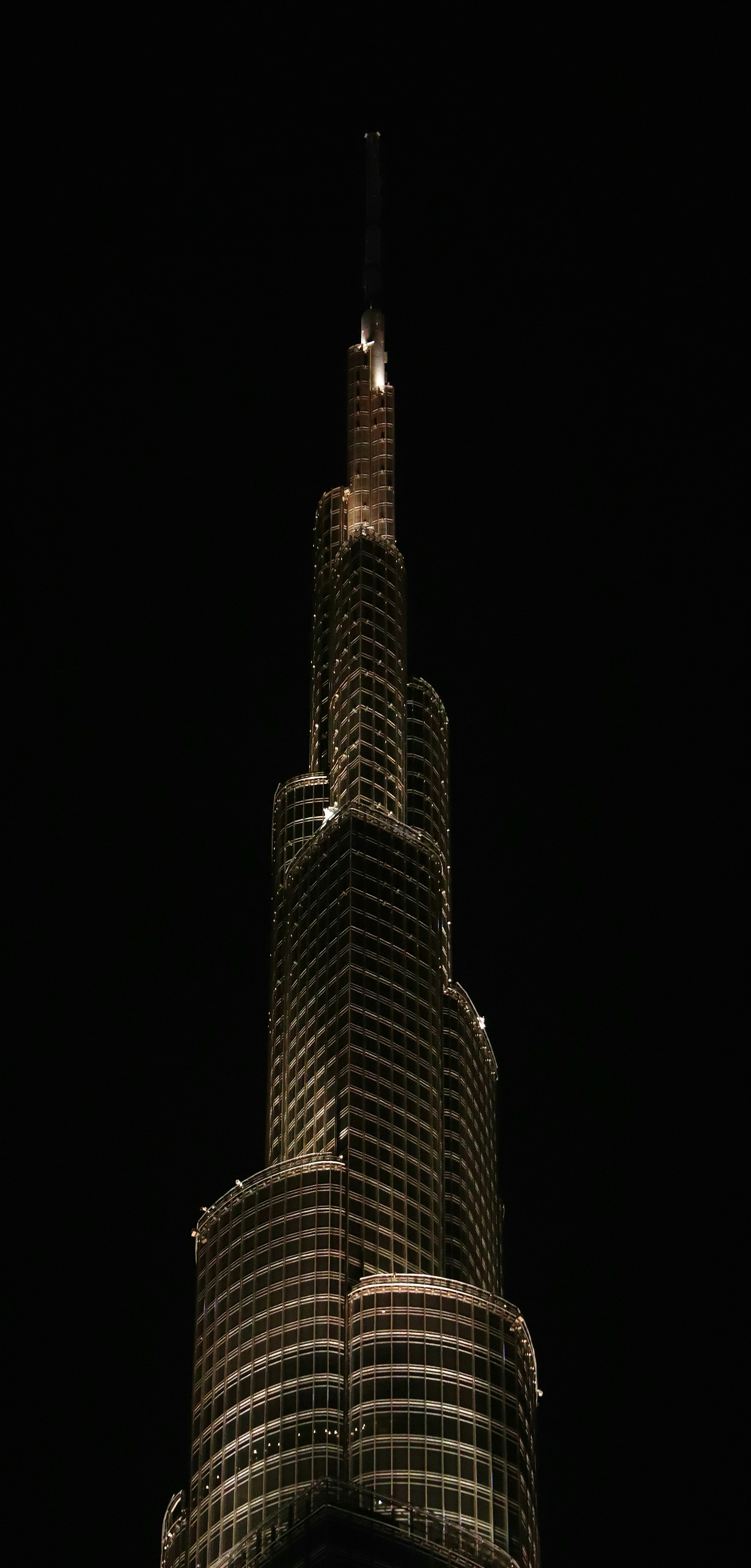Tall skyscraper illuminated at night against dark sky