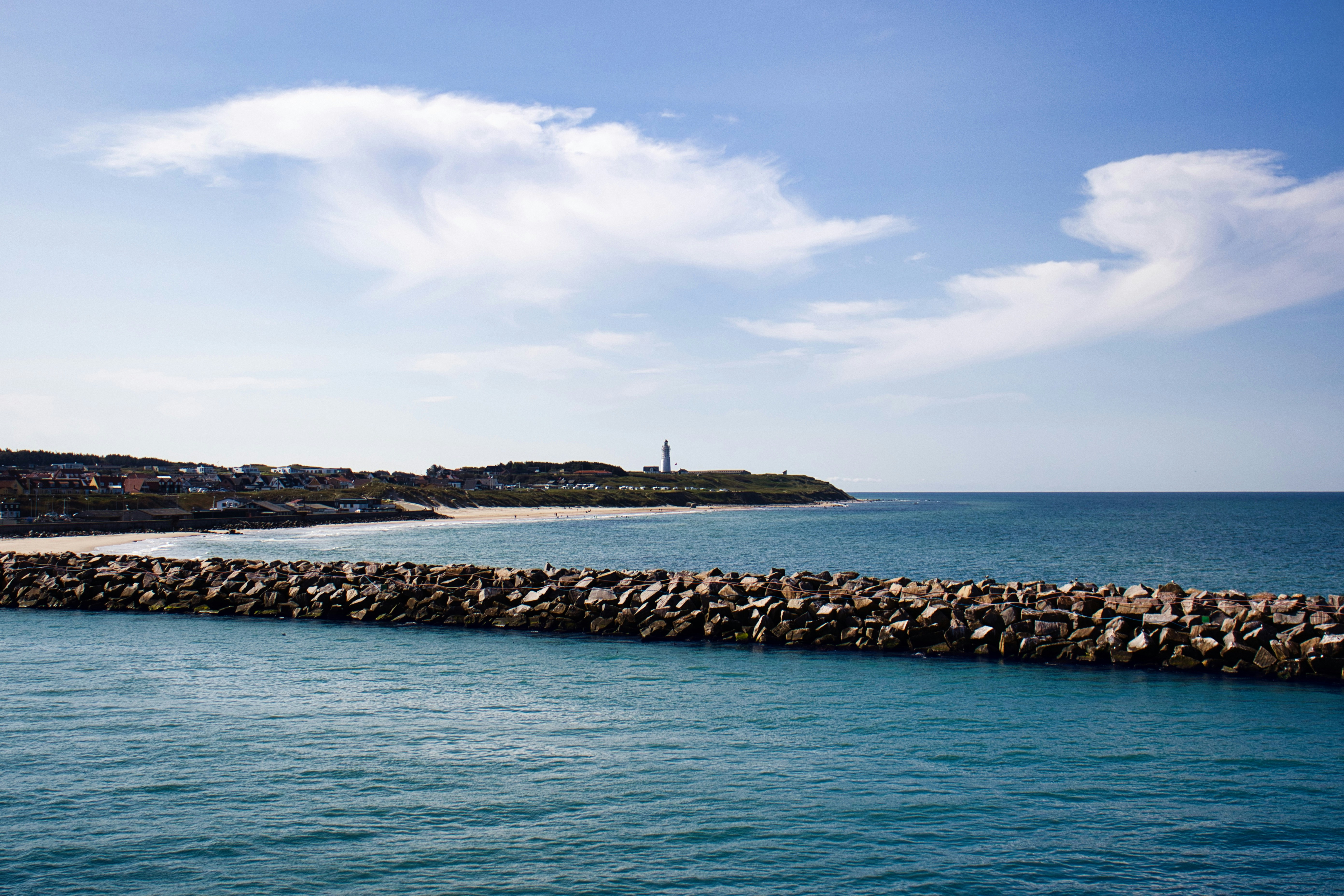 Ocean waves break against a rocky breakwater by the coast.