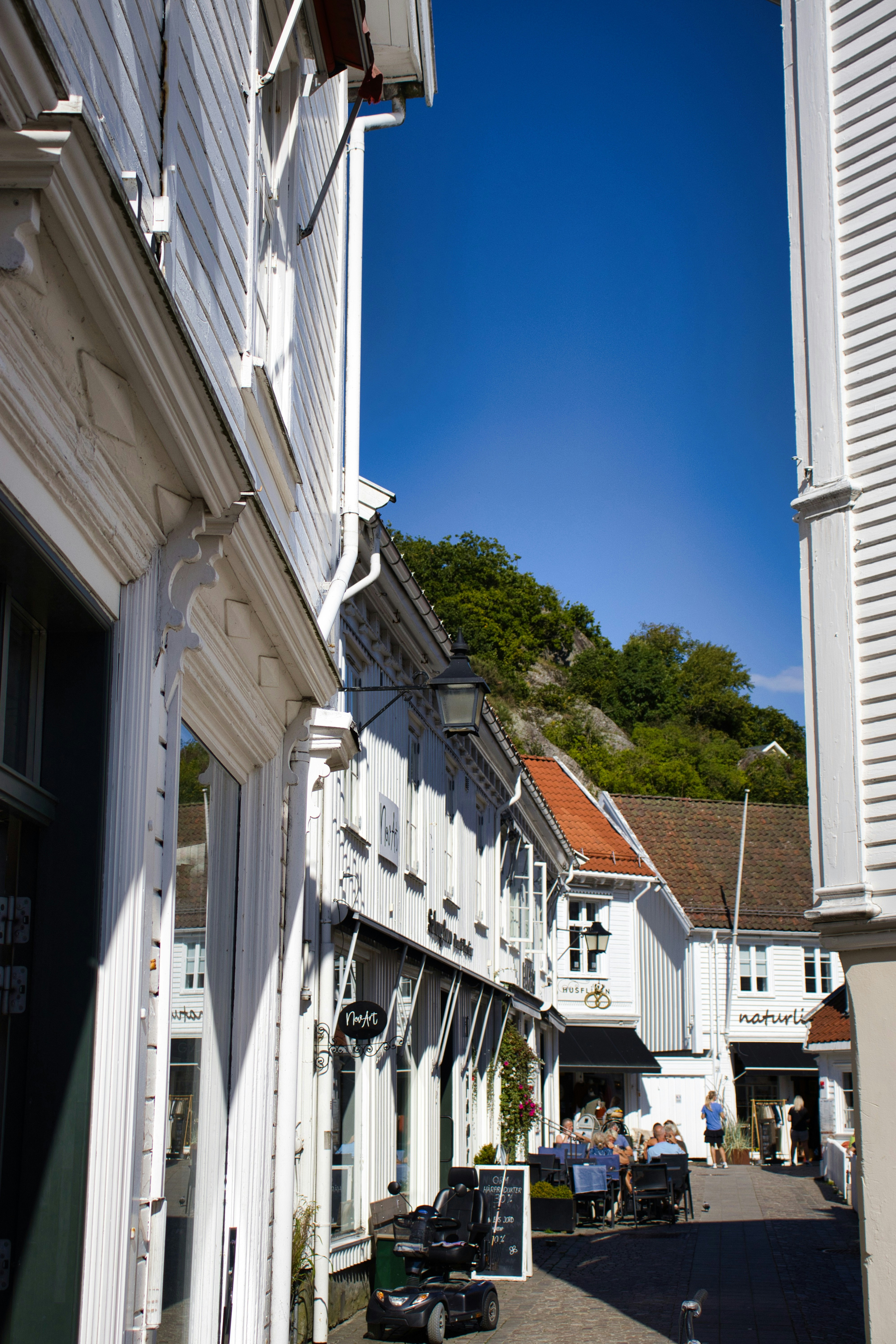 White buildings line a narrow street under blue sky.