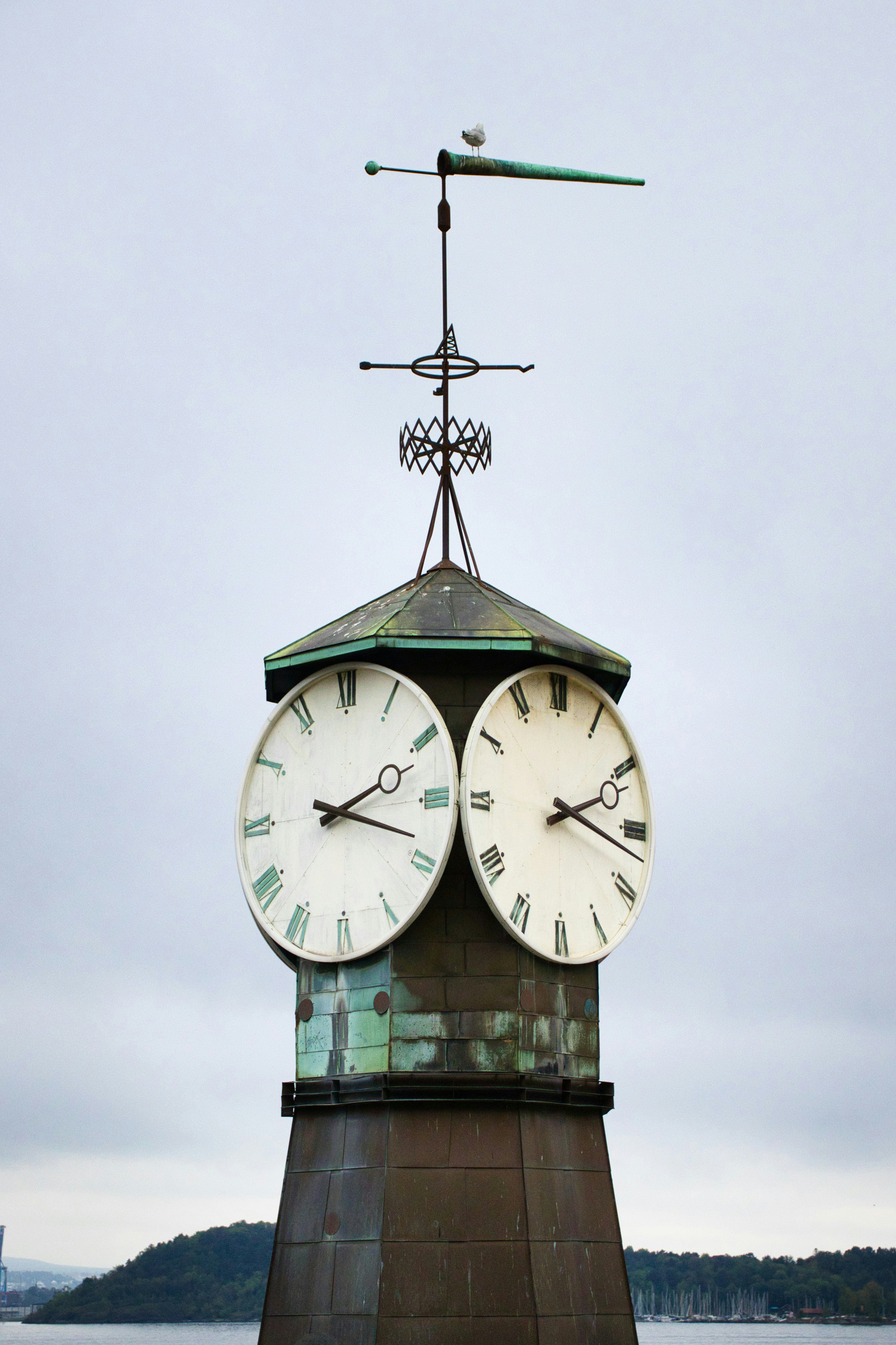 A clock tower with two faces and a weather vane