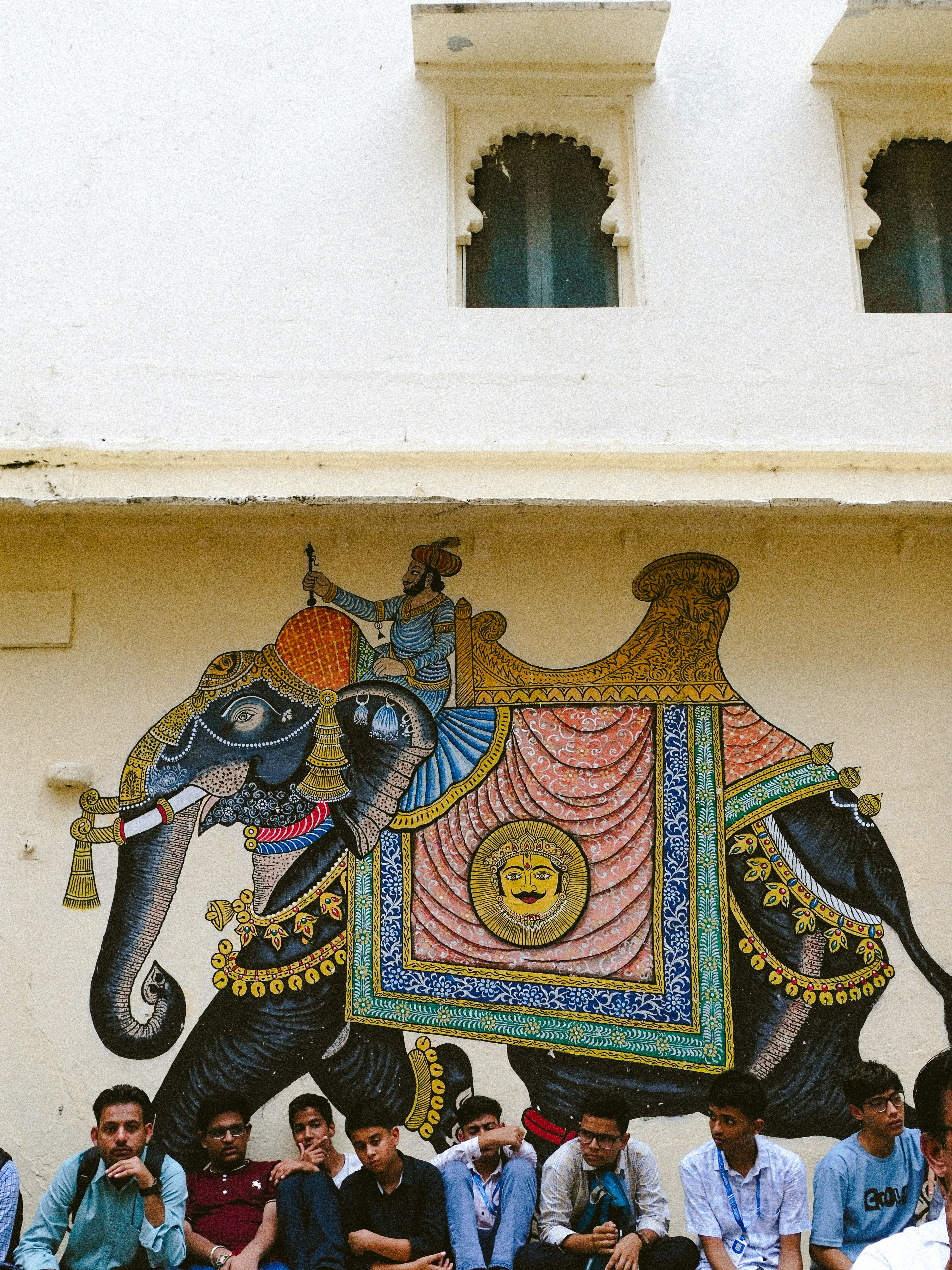 Ornate elephant mural with people sitting below