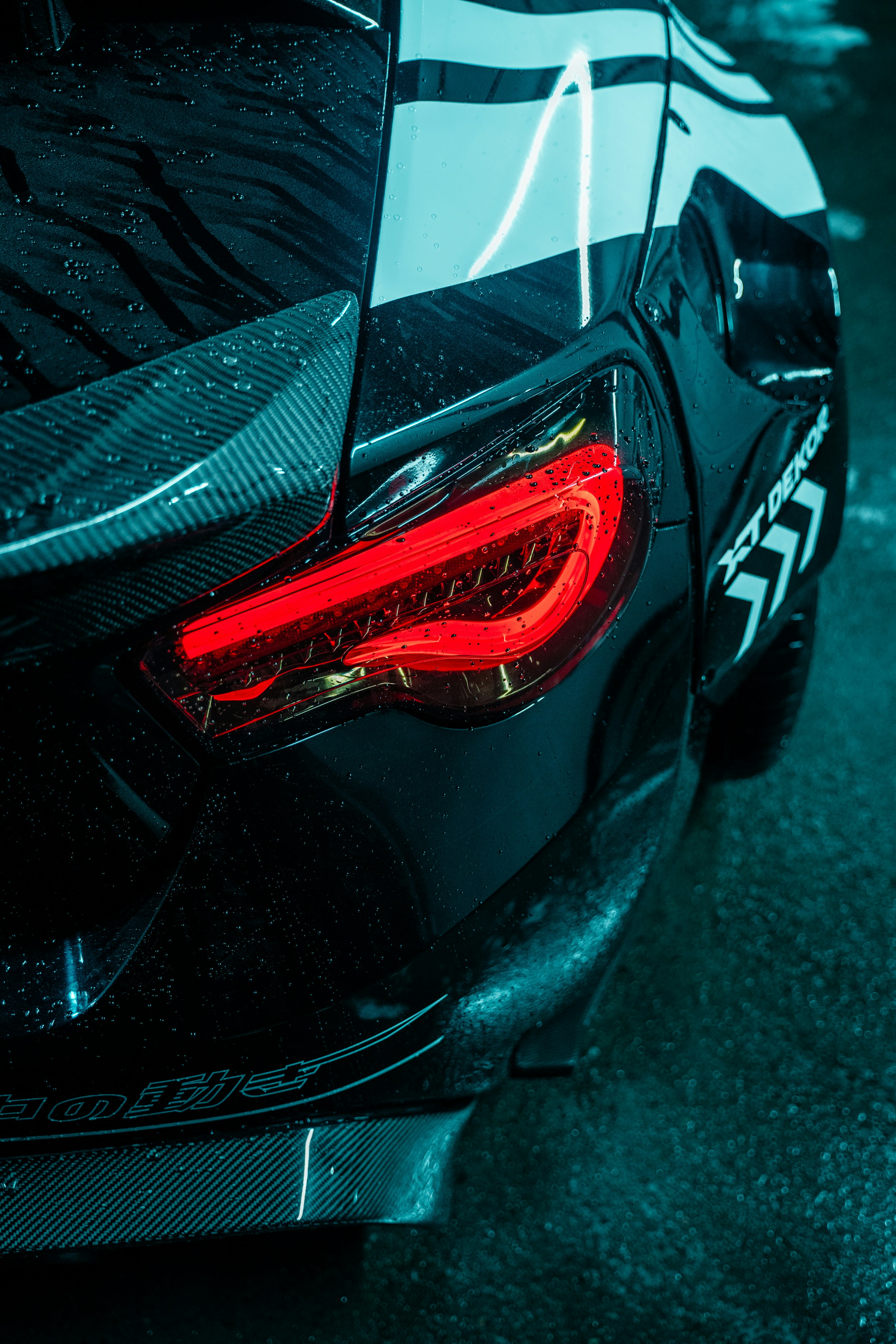 Subaru BRZ Rocket Bunny V3 | Close-up of a wet sports car taillight at night.