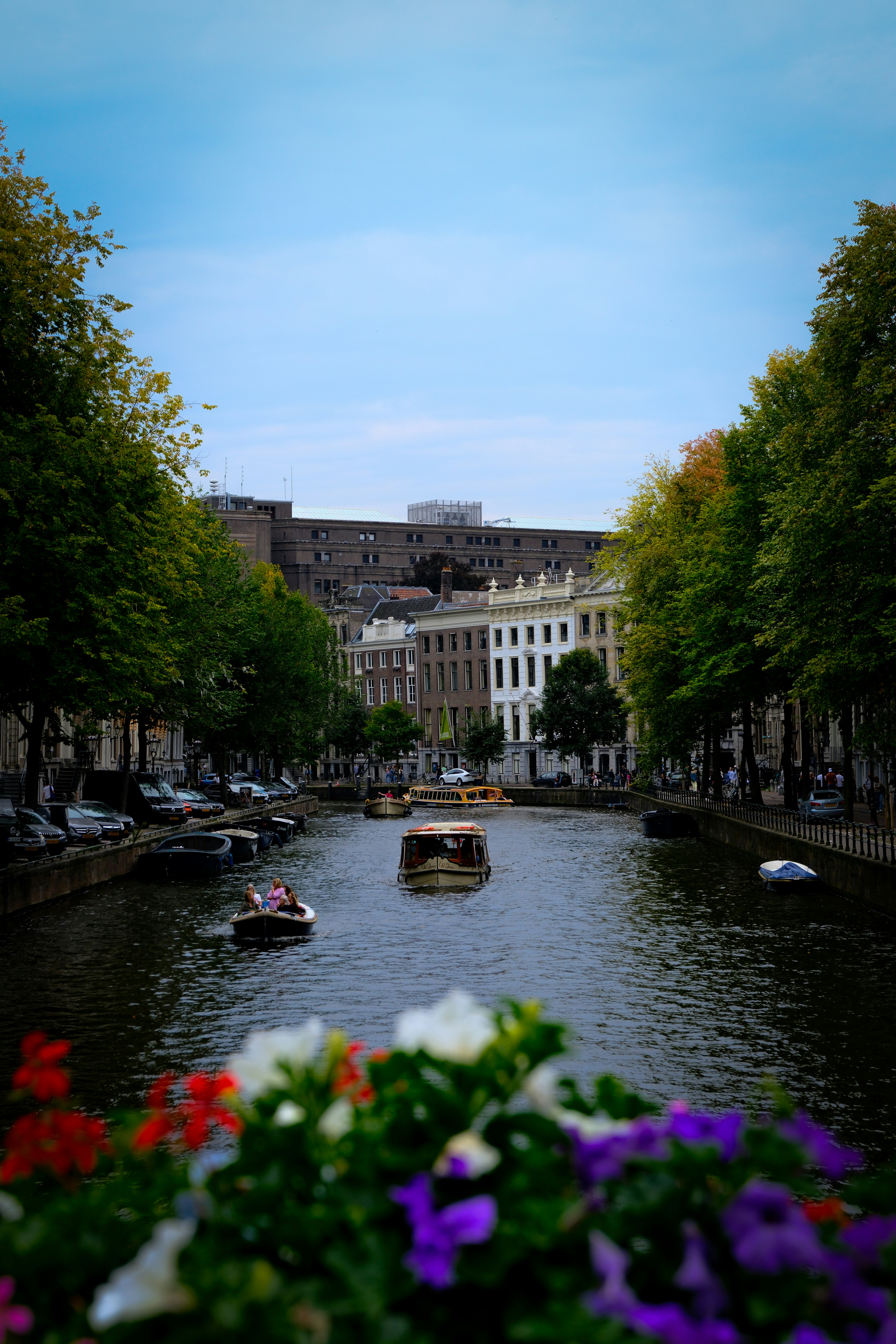 Boats on a canal lined with trees and buildings.