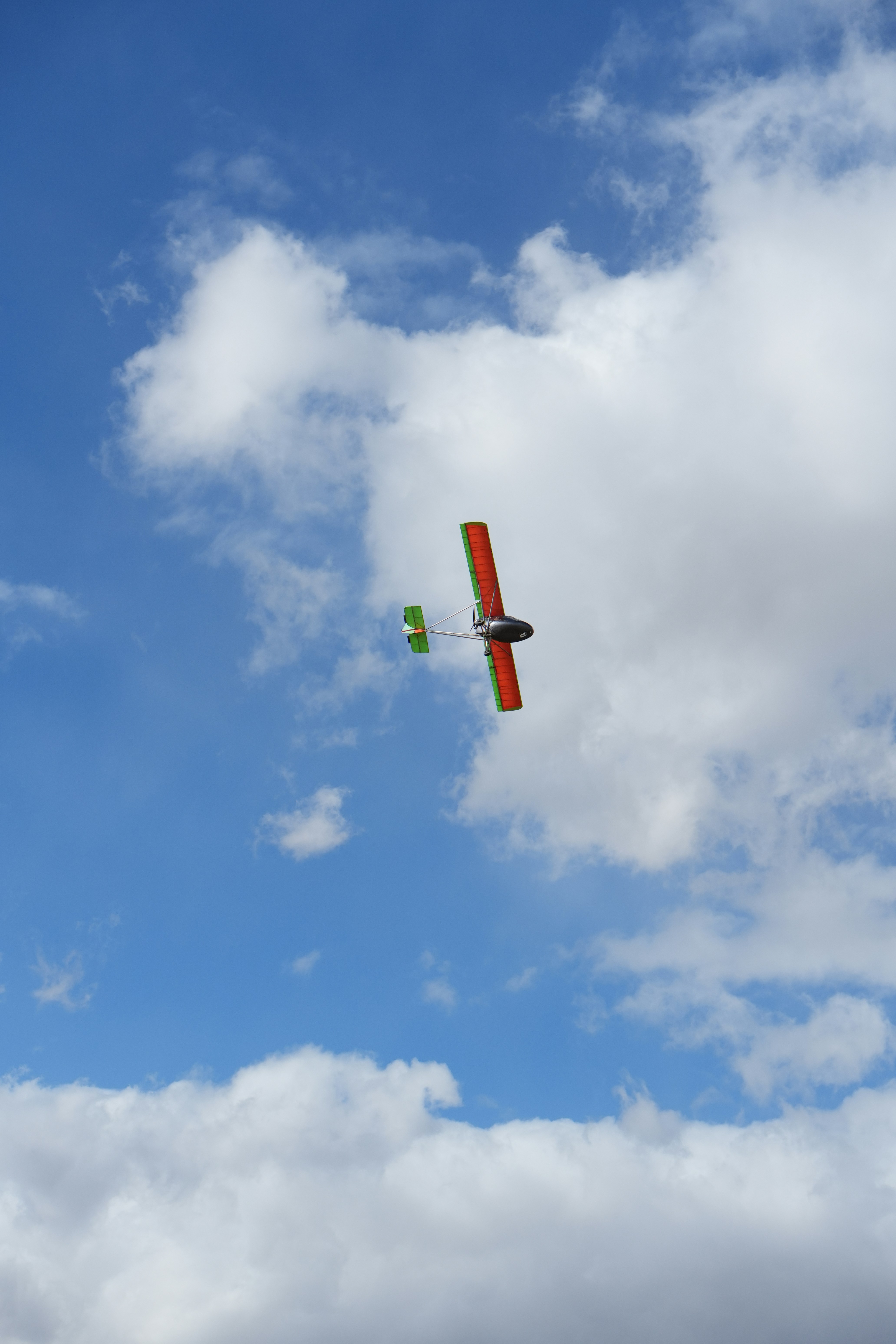 Small drone flying in a blue sky with clouds