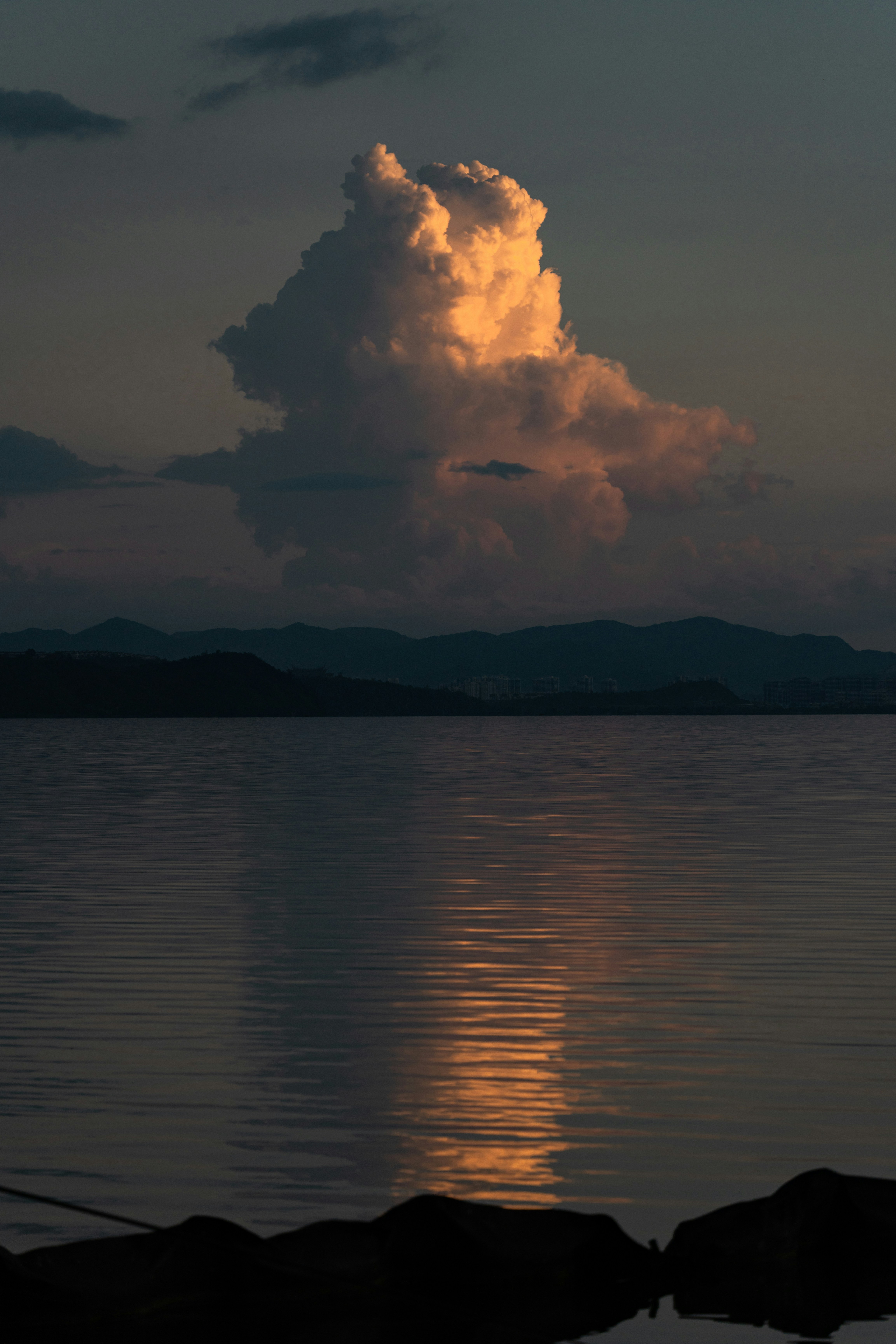 A single cloud illuminated by sunset over calm water.