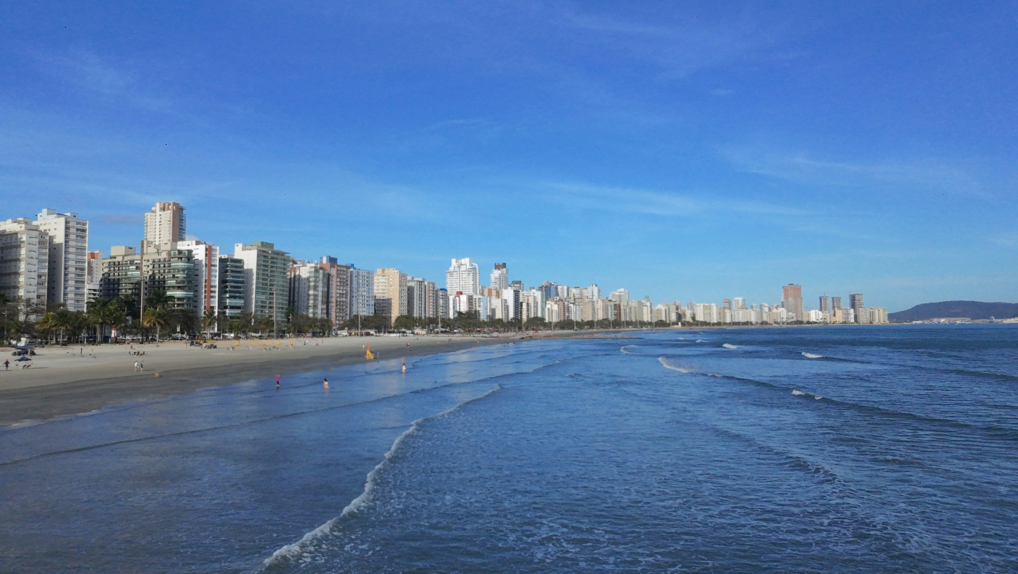 City skyline along a sandy beach with ocean waves.