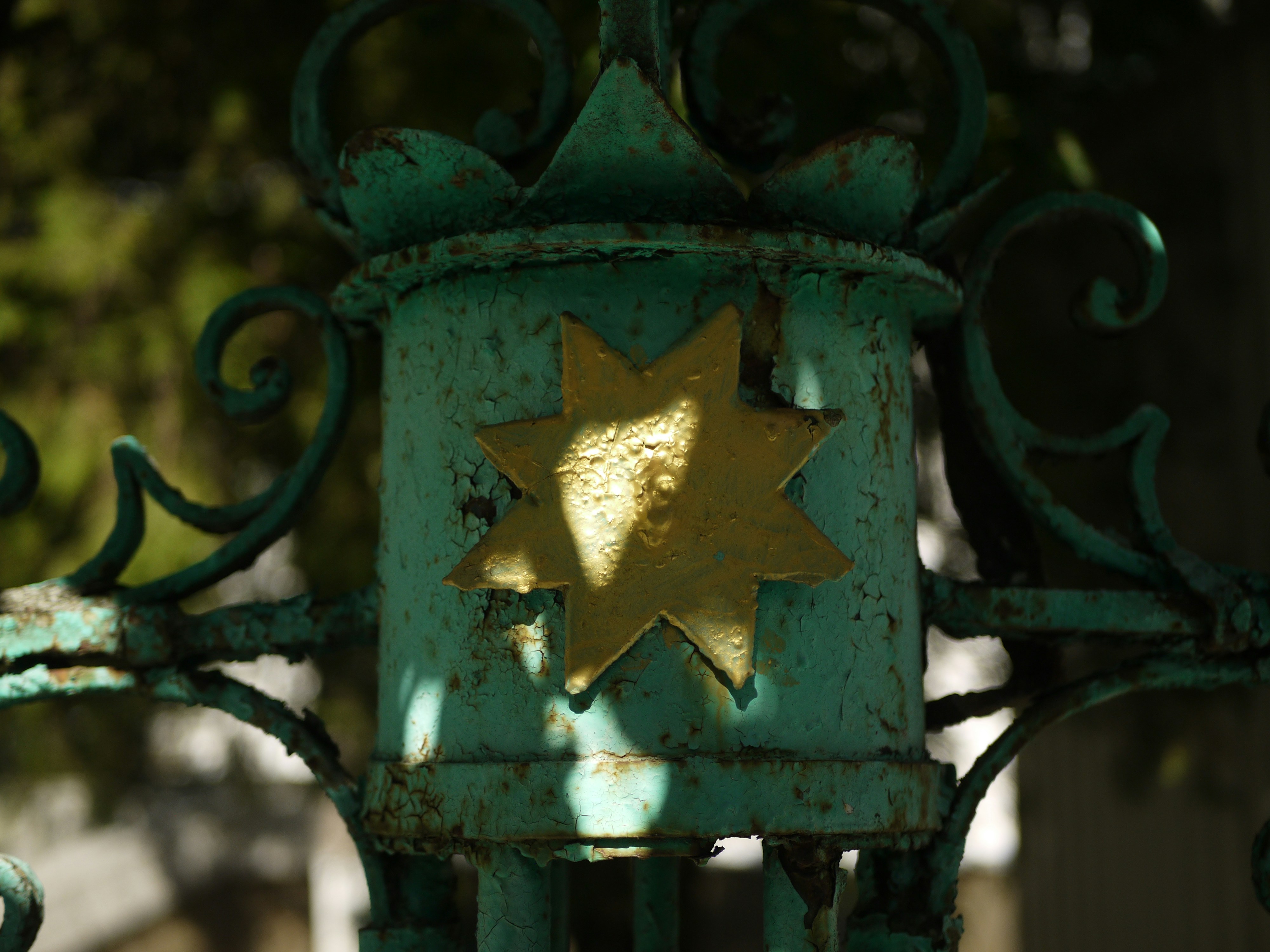 Green ornate gate with a gold star emblem.