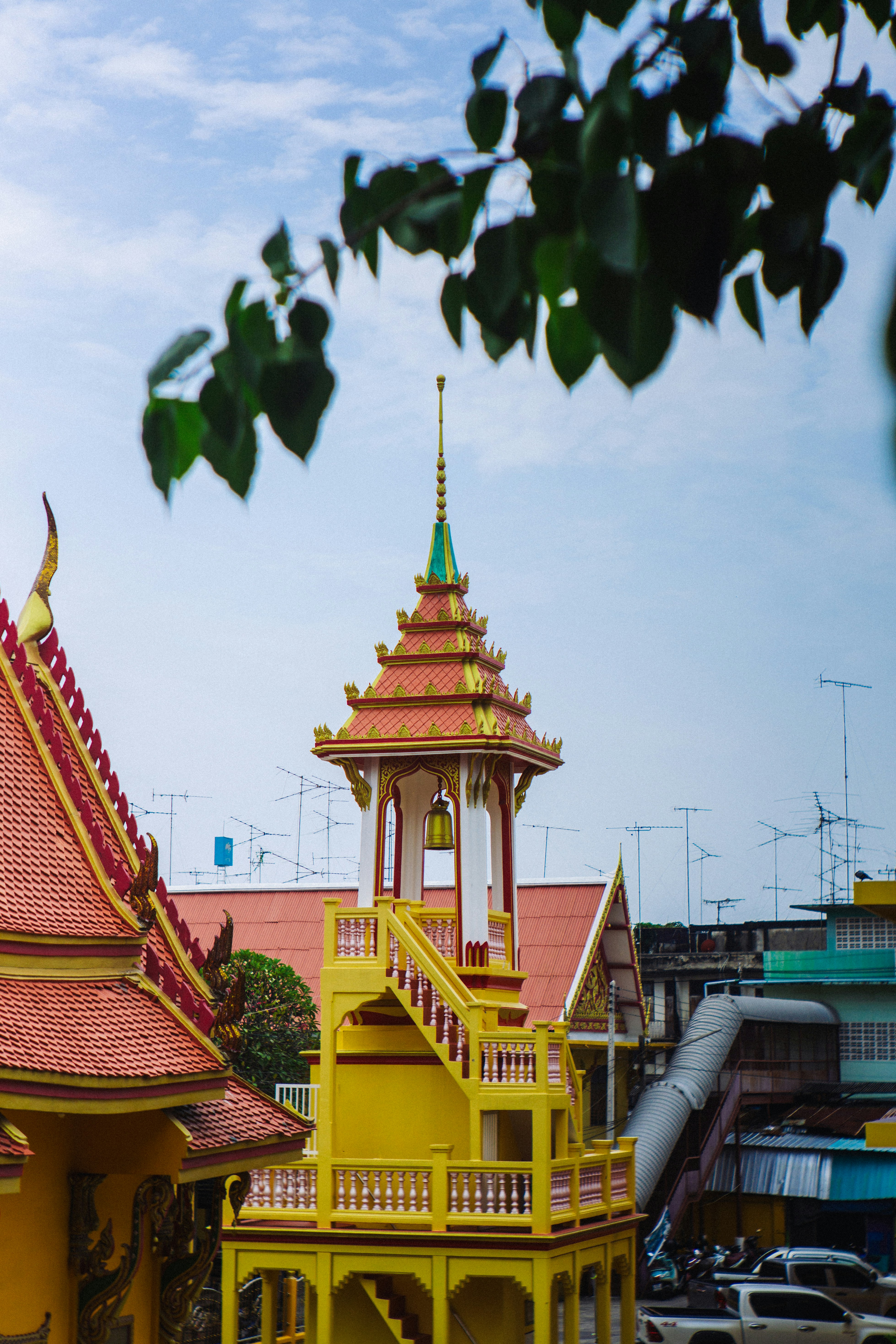 Ornate thai temple tower against a cloudy sky.