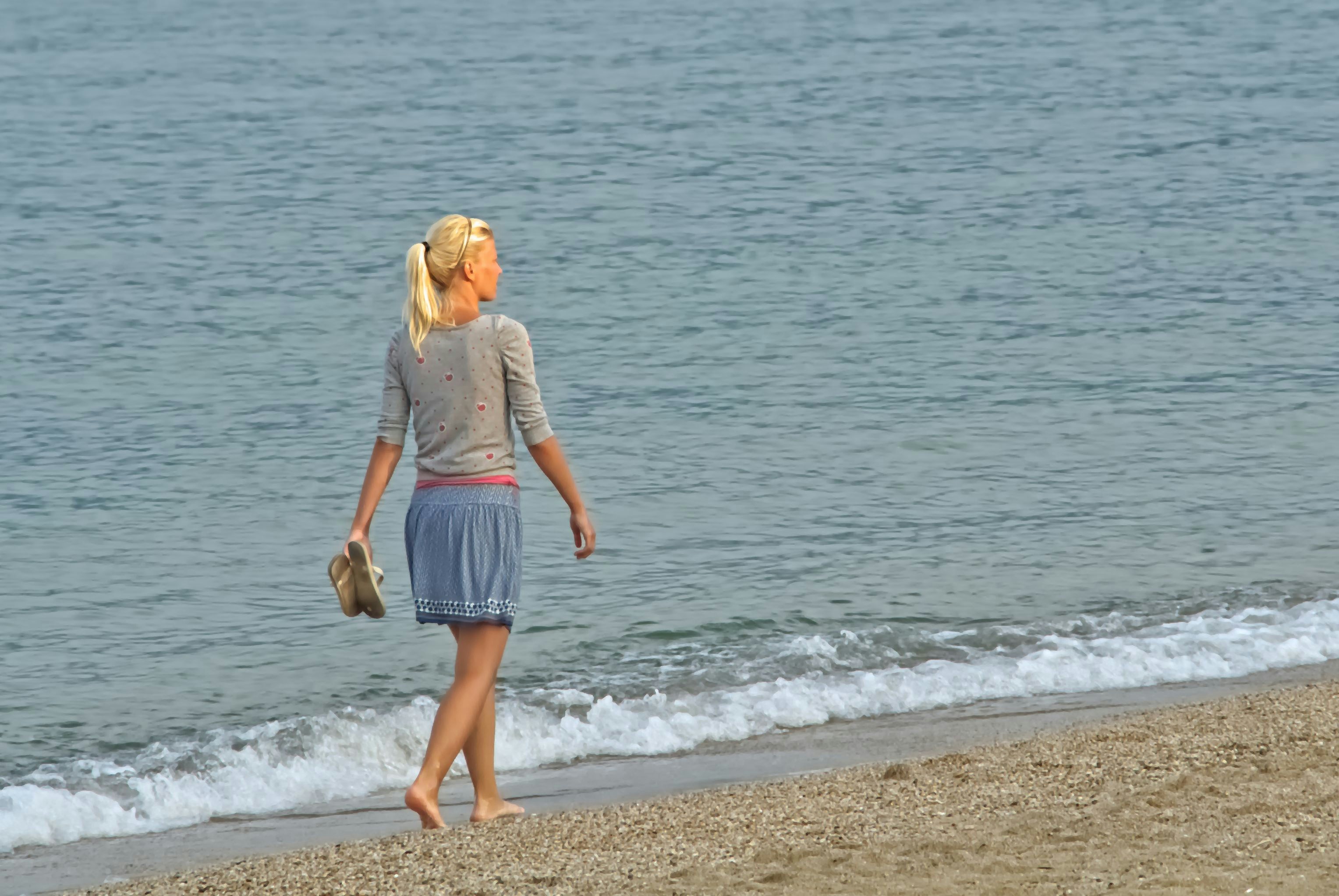 Woman walking on beach next to the ocean