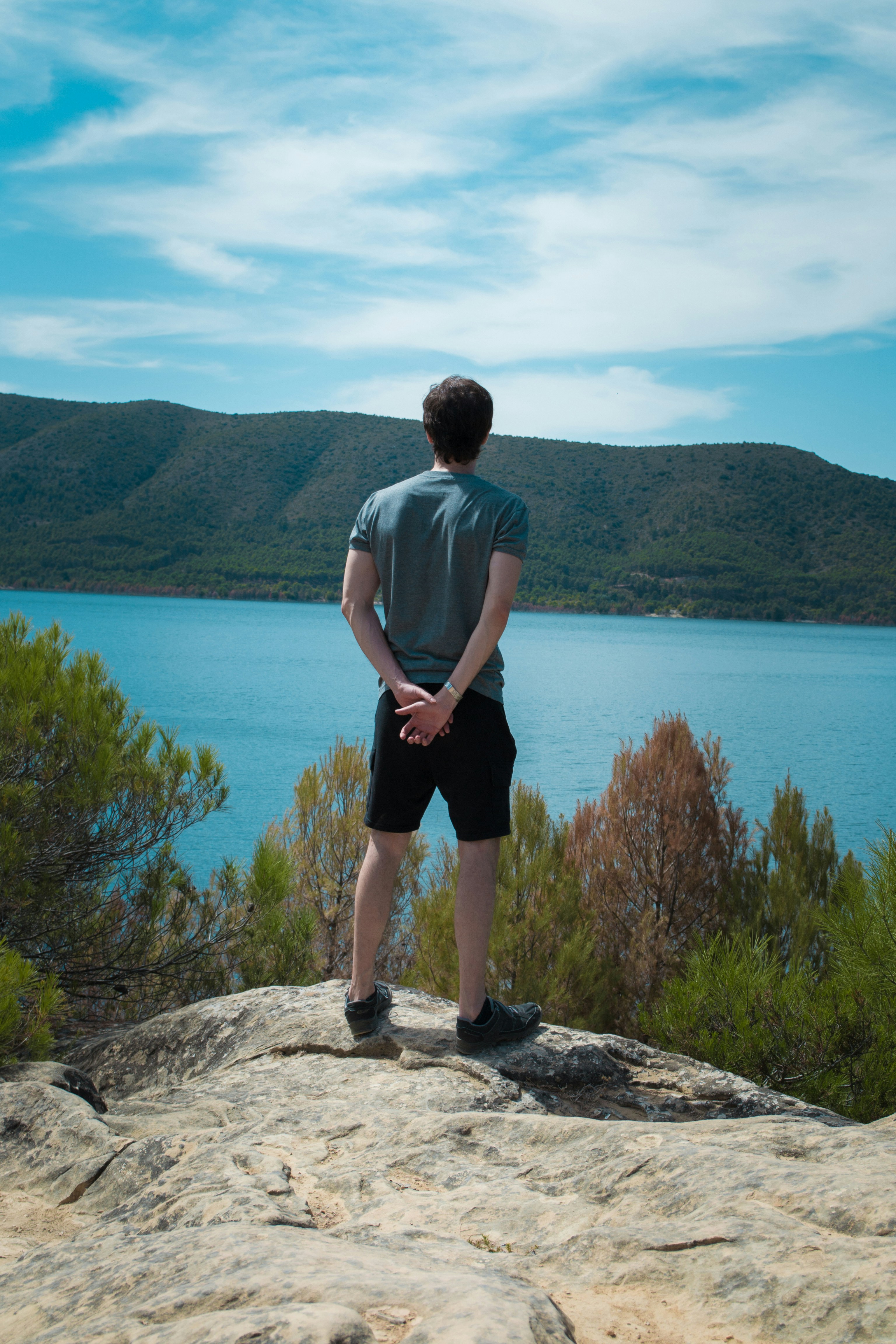 Edge of Stillness: A Man Stands on Granite Over a Turquoise Lake