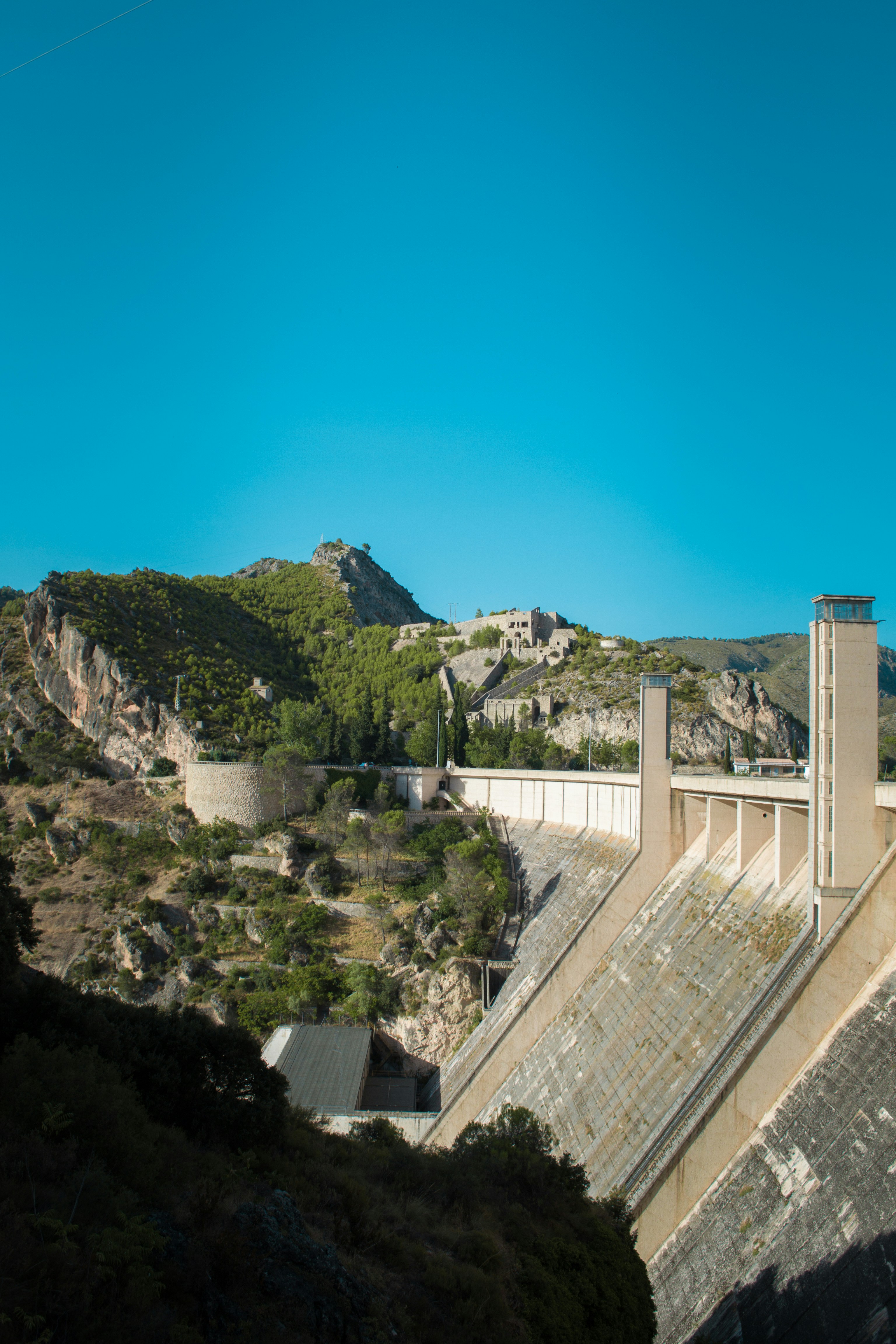 Rising Crest: A Dam and Hilltop Fort Amid Blue Sky