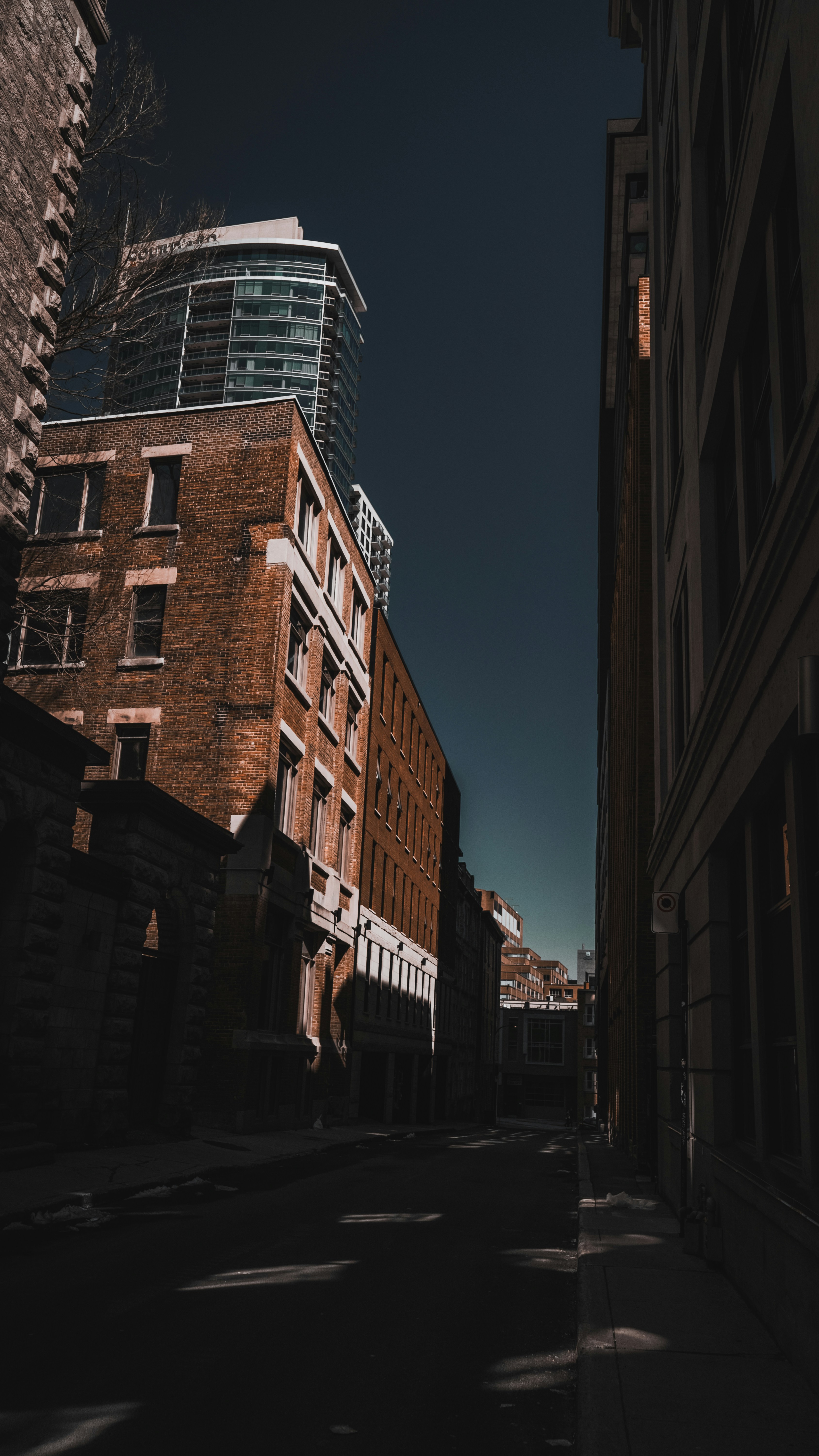 Narrow city street with brick buildings and shadows