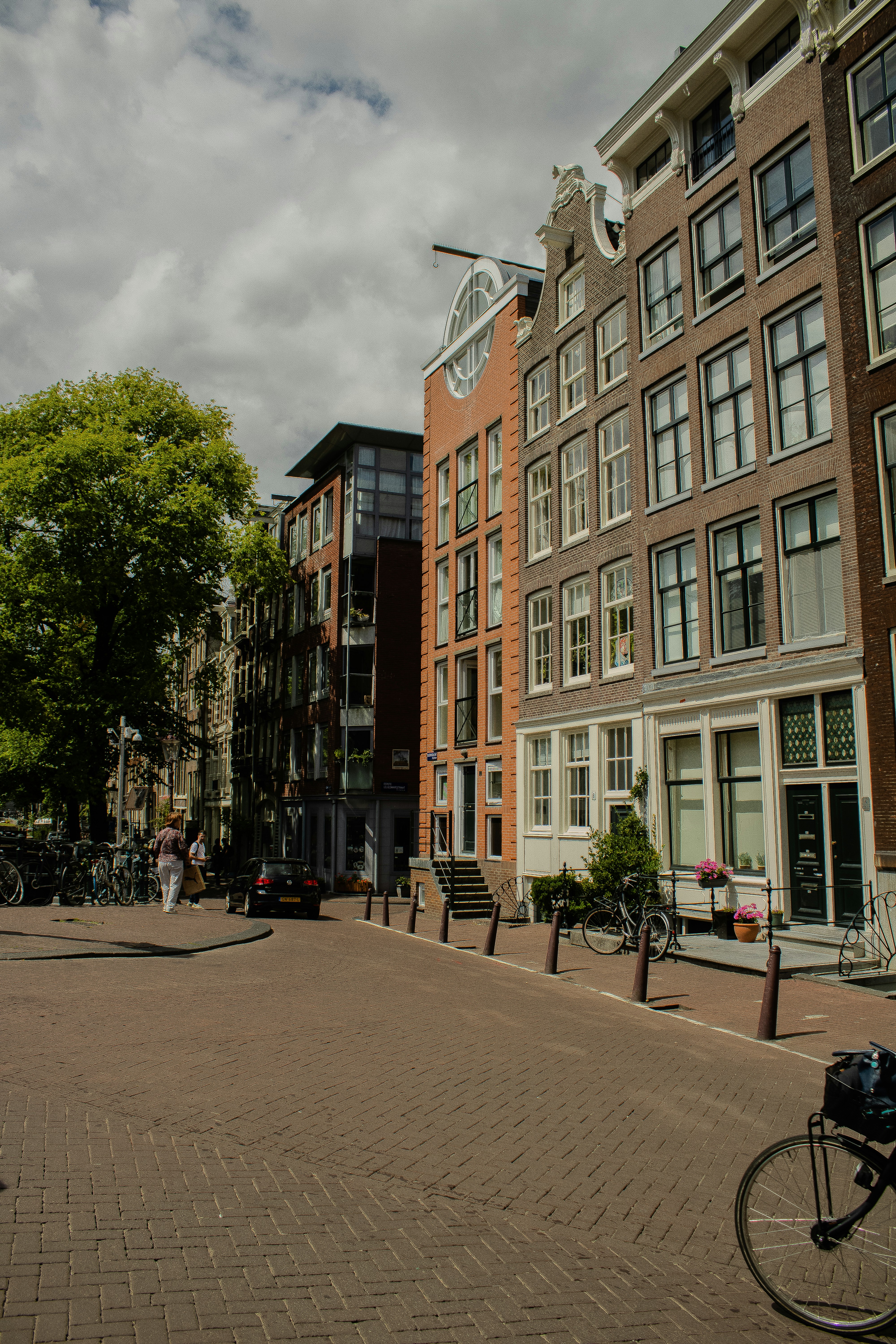 Walking around amsterdam architecture | Tall buildings line a brick street in amsterdam.