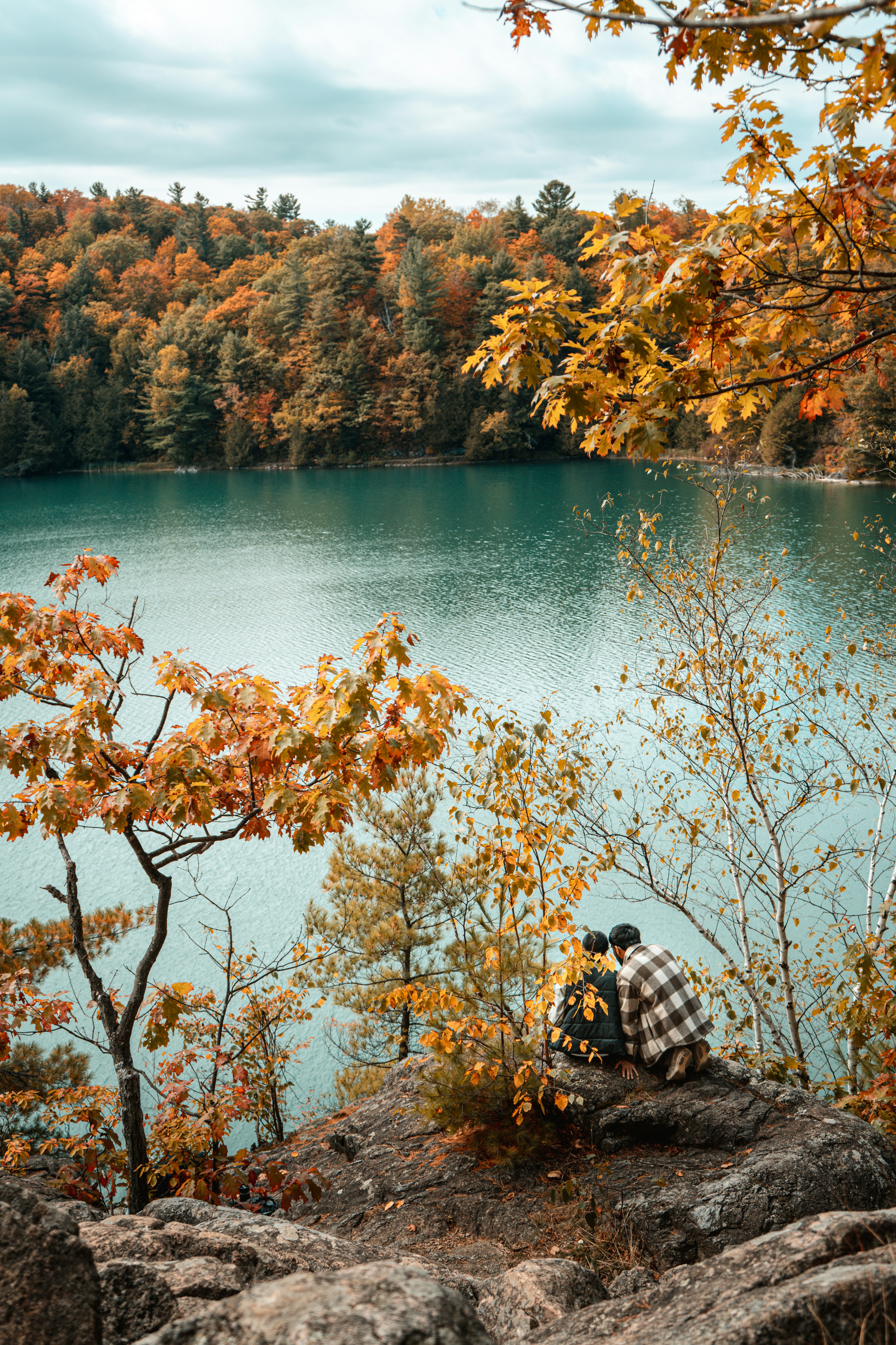 Couple watches autumn foliage by tranquil lake