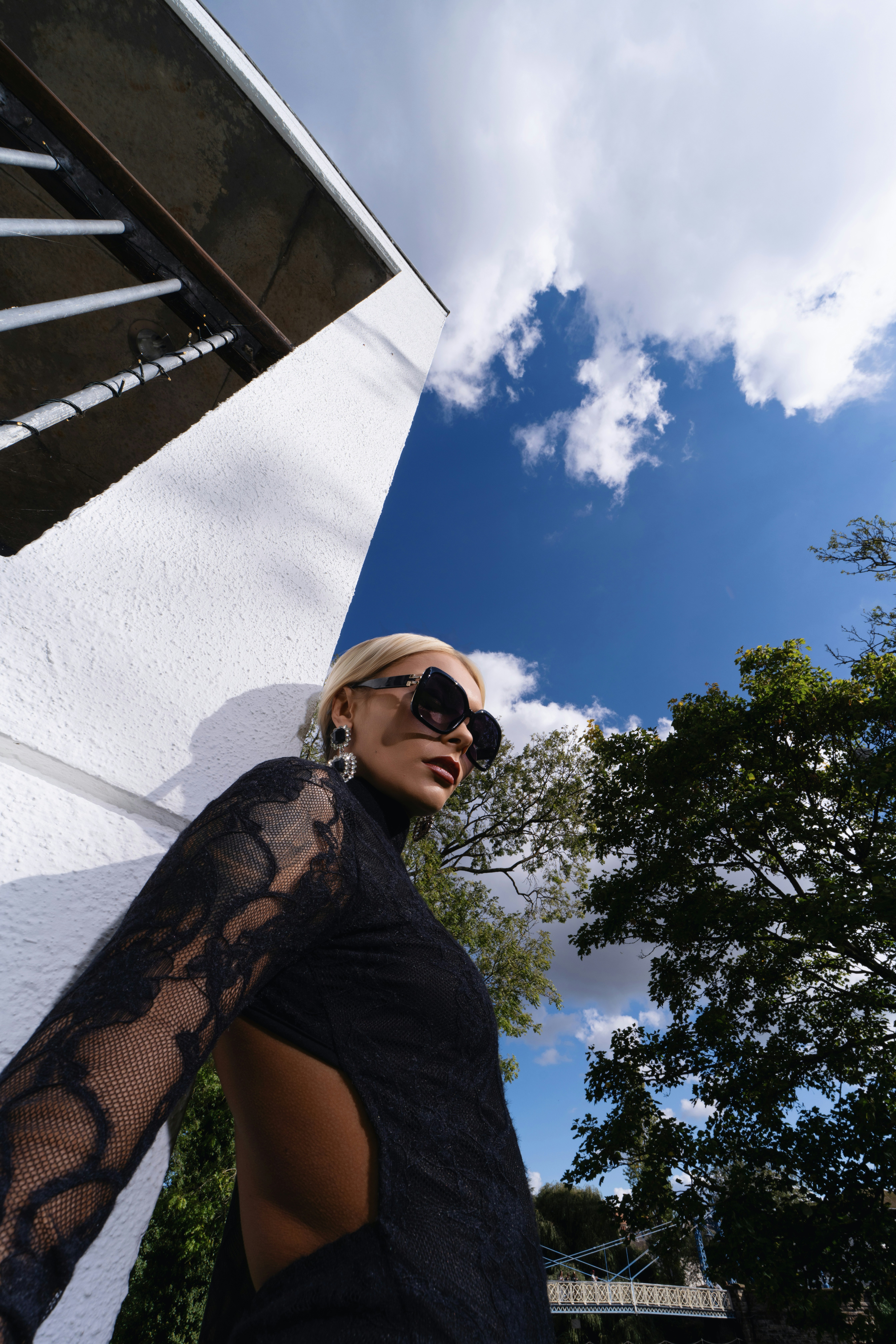 Lace and Light at Ground Level: A Portrait Against Sky and Wall