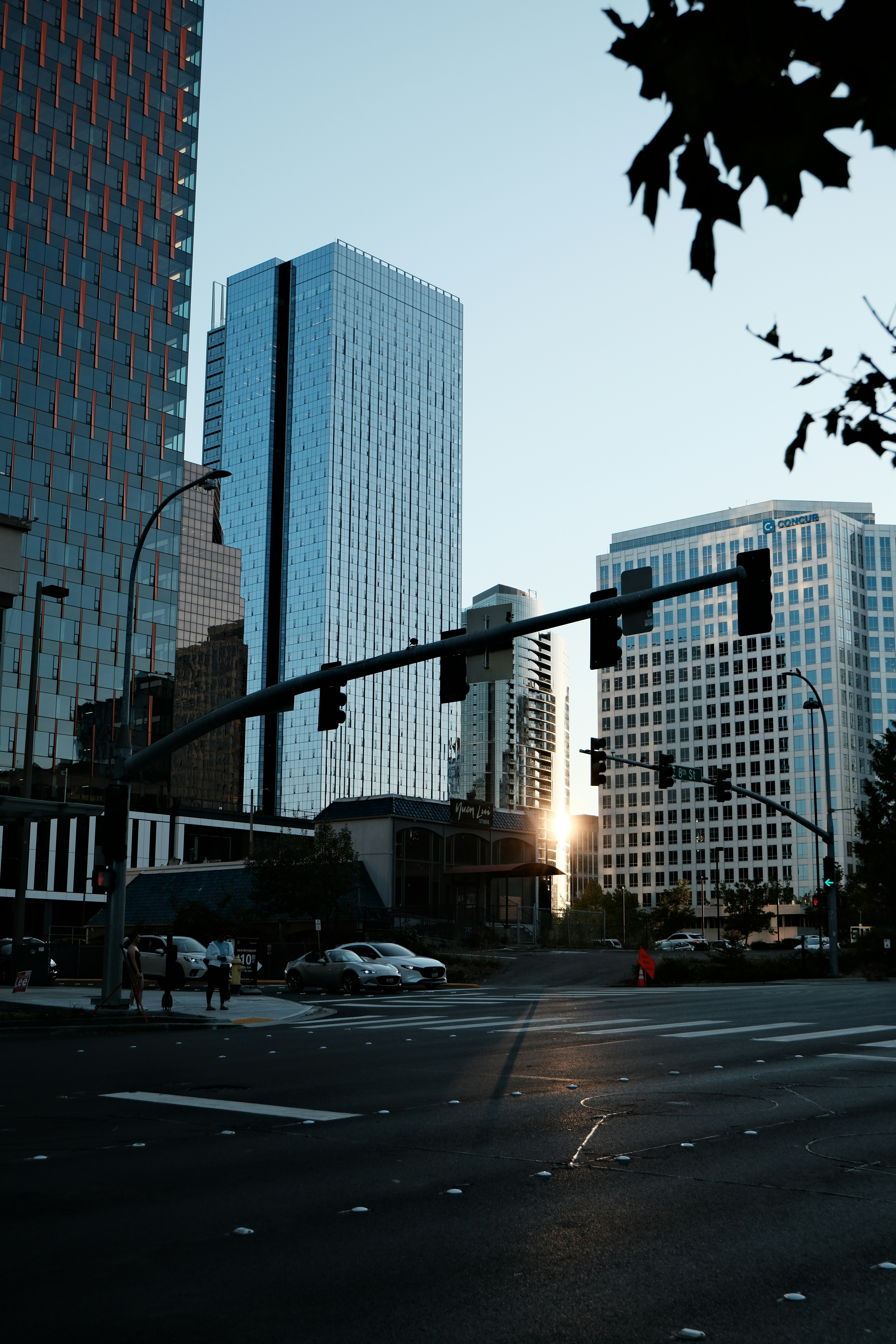 Modern skyscrapers at a city intersection during sunset.
