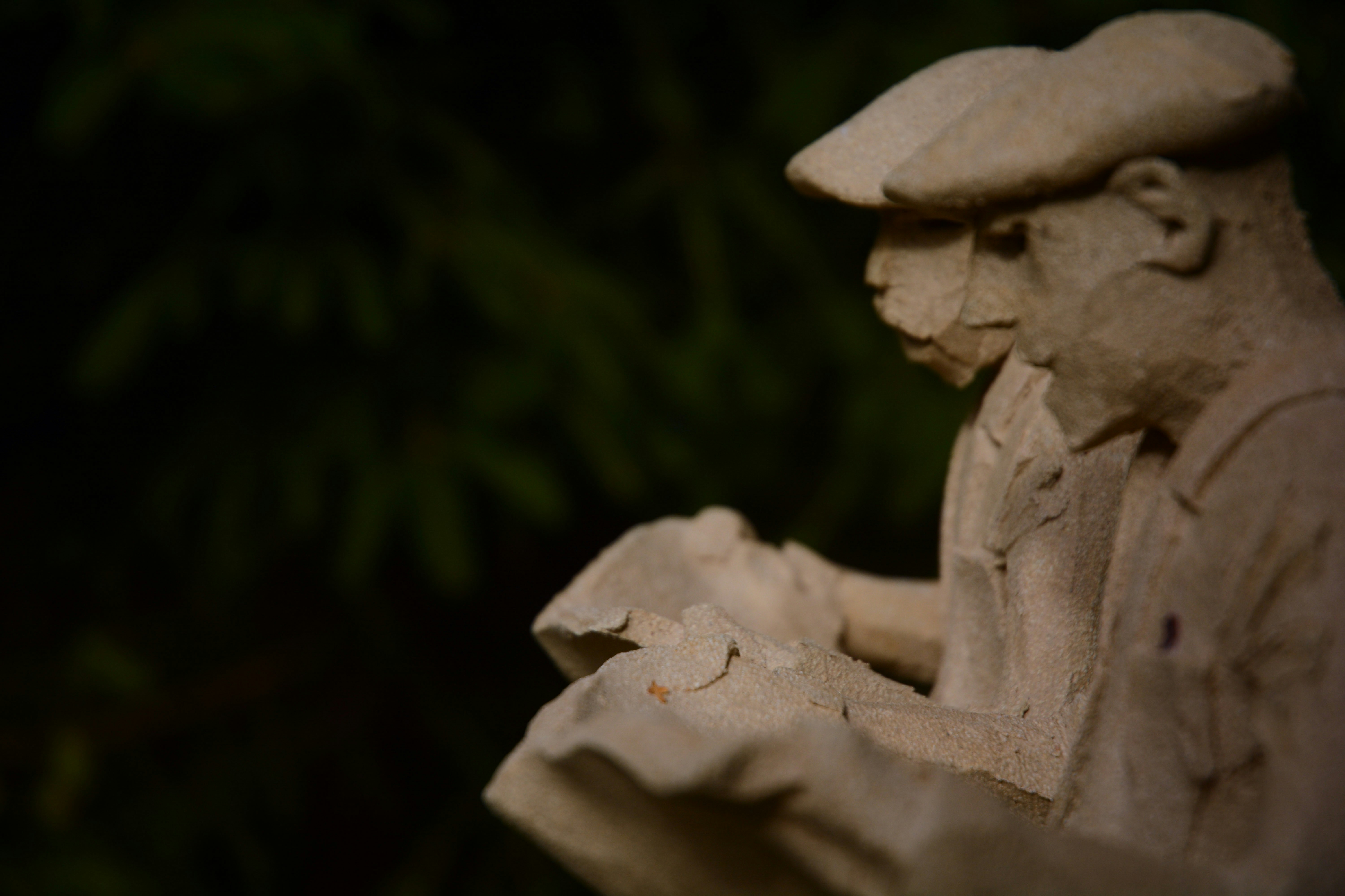 Two stone figures in flat caps working together.