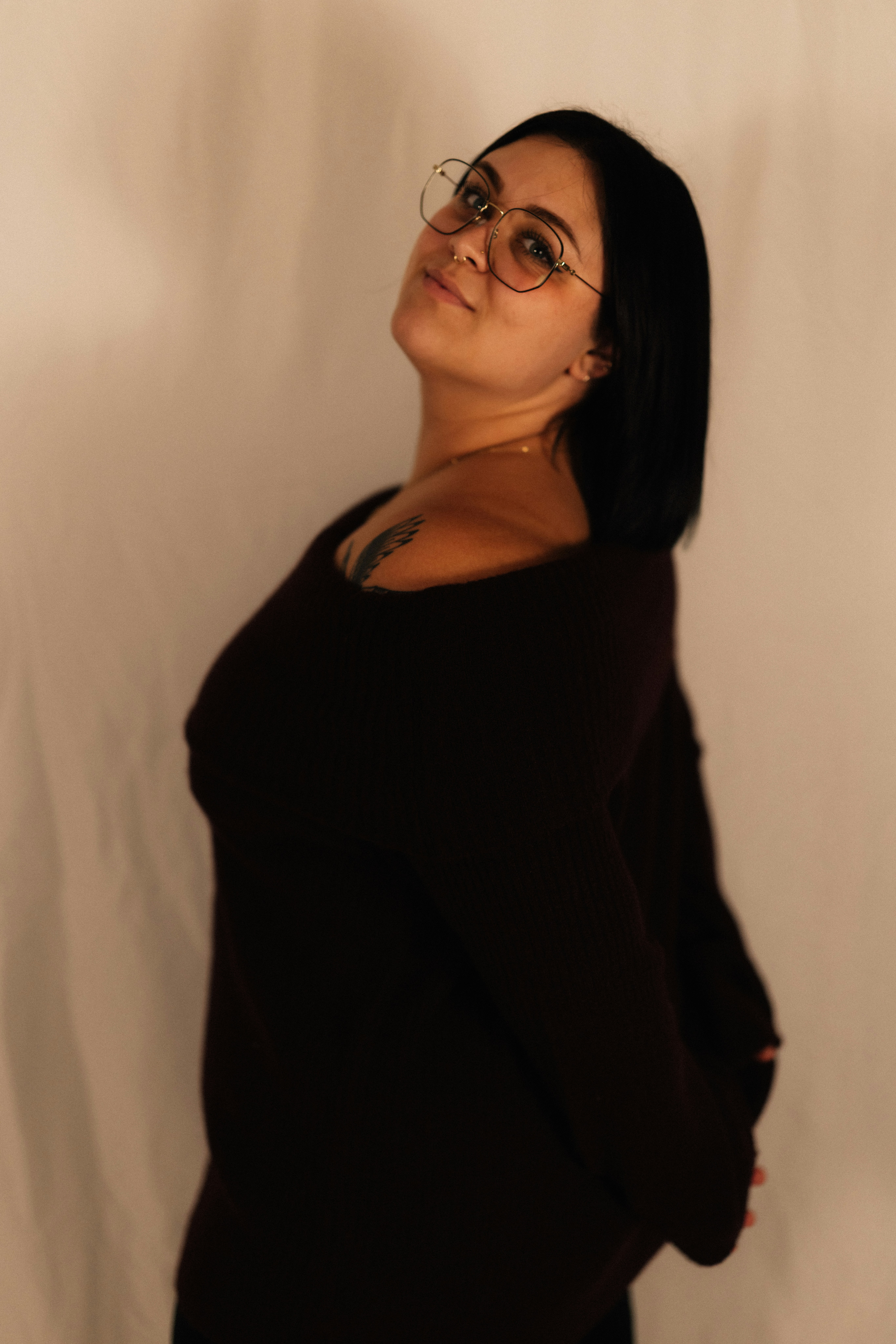 Woman with glasses and dark hair looking over shoulder