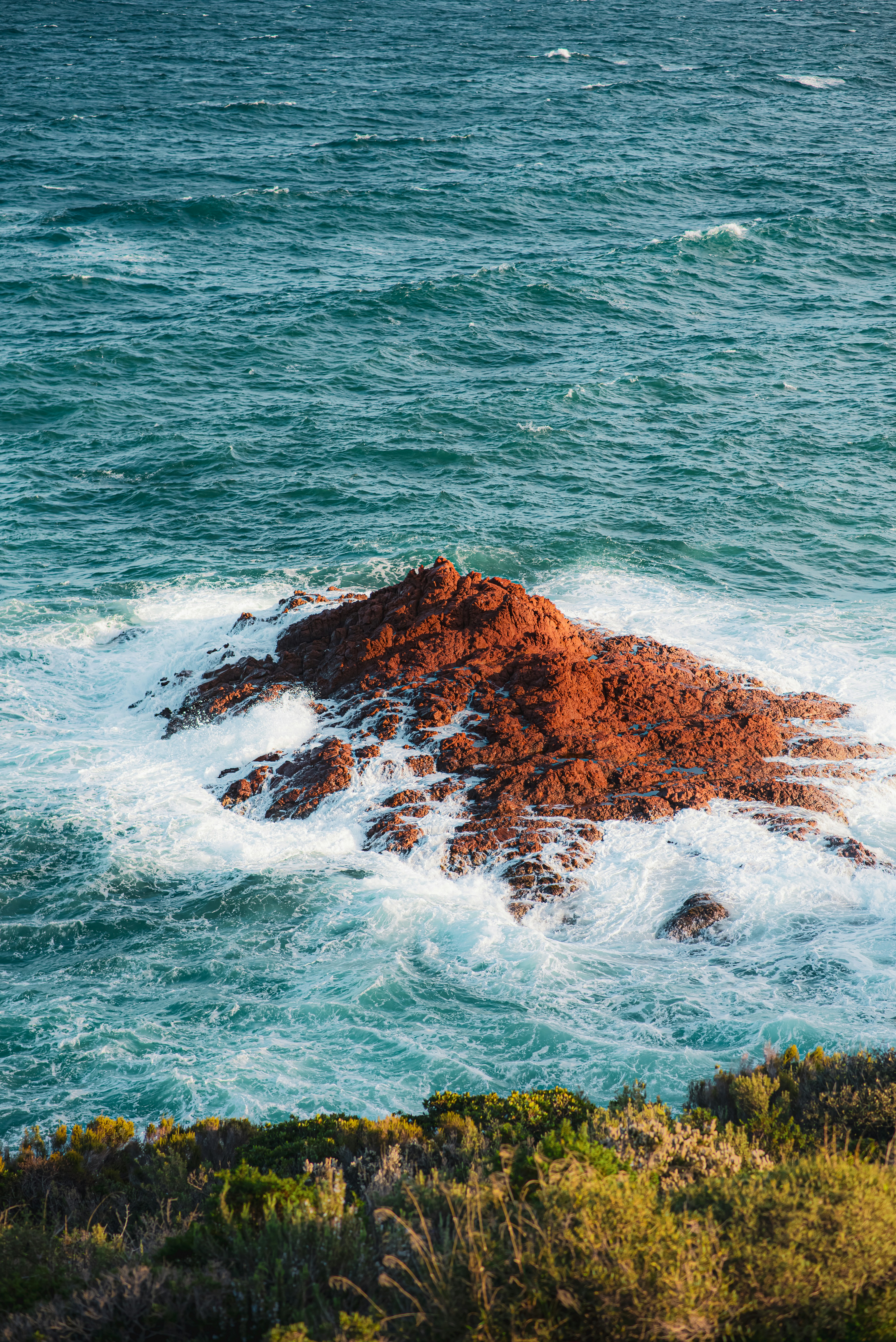 Red rock formation battered by ocean waves