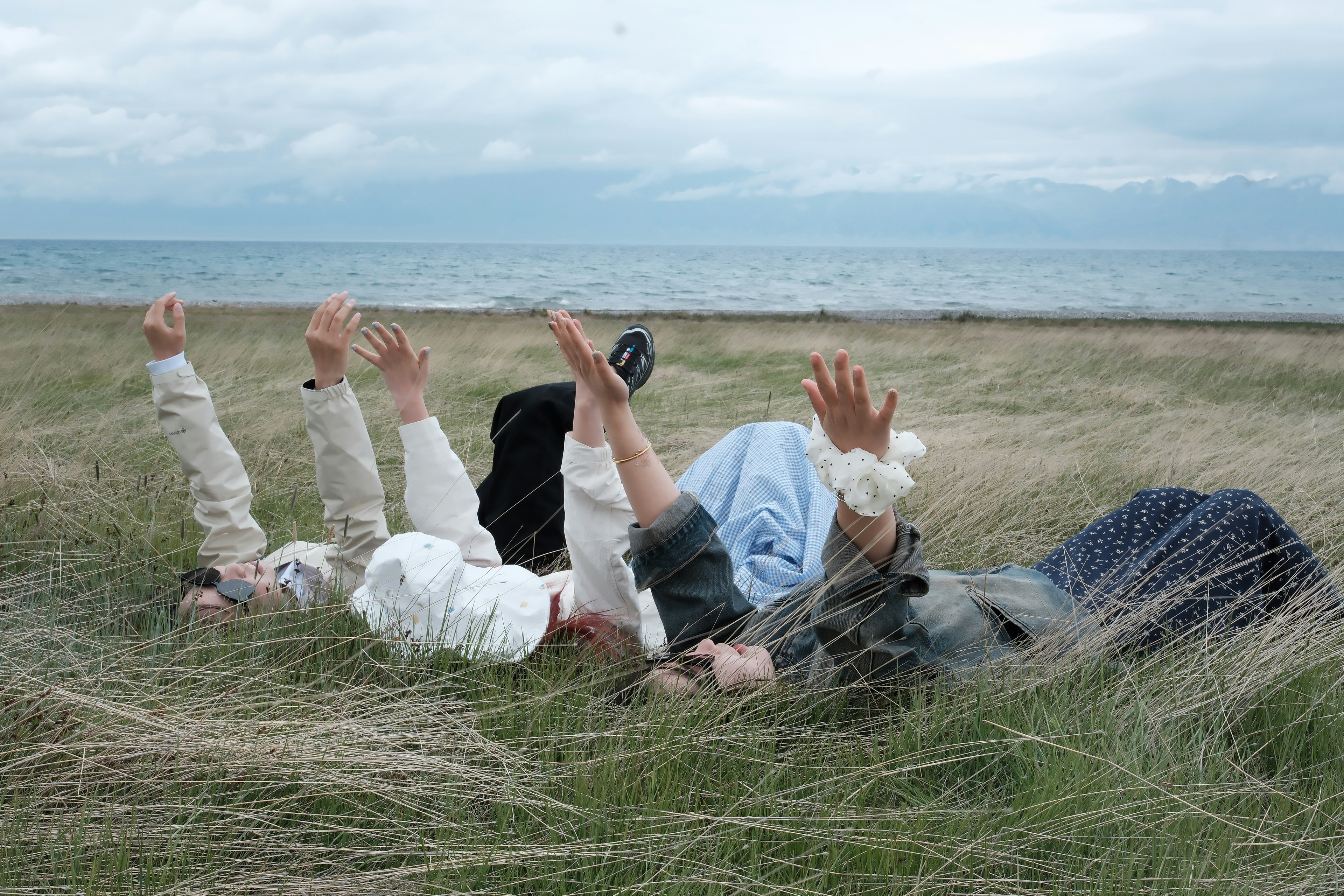 People lying in grass with arms raised