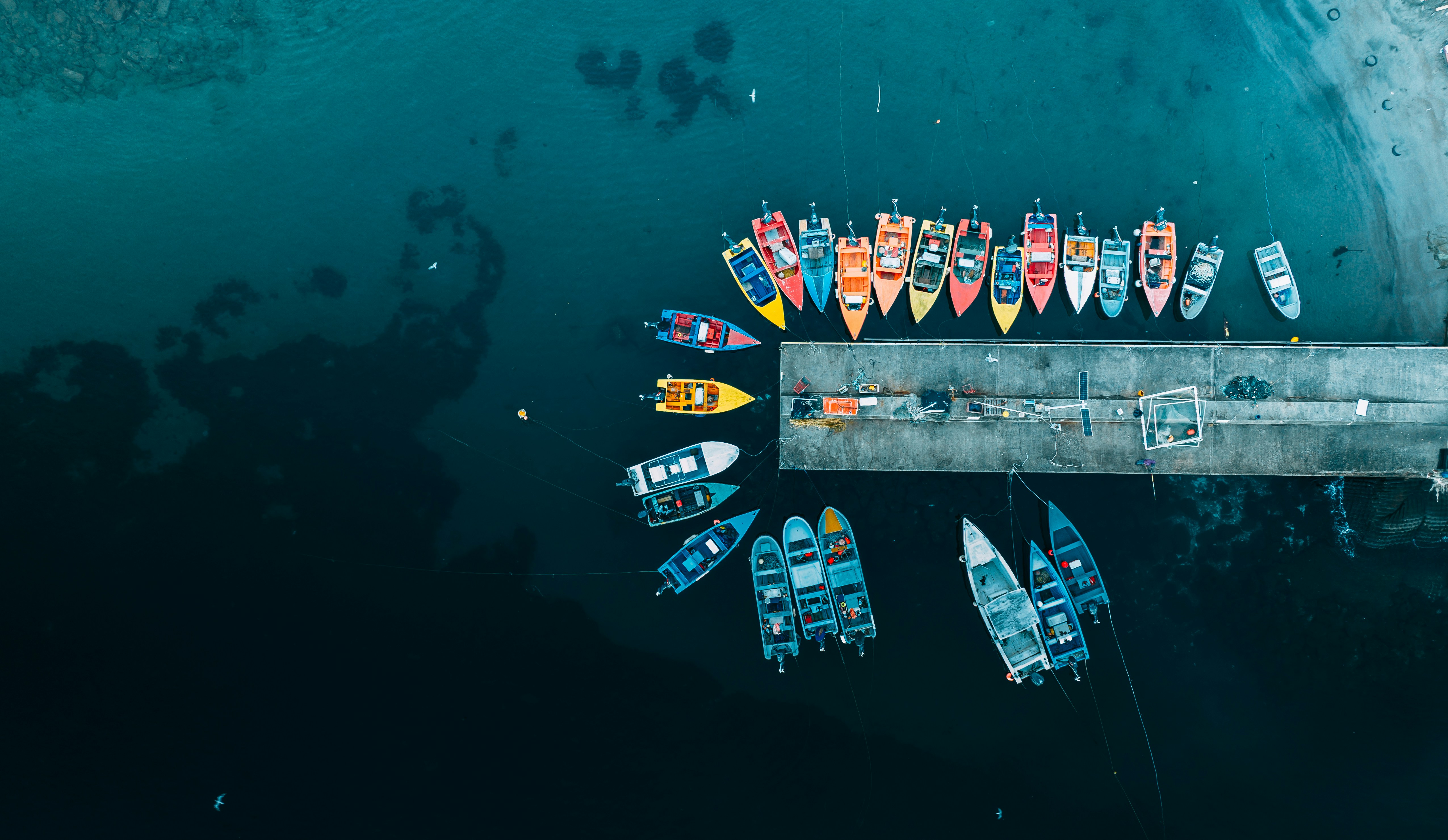 Fishing Boats | Colorful boats docked at a pier on a dark day