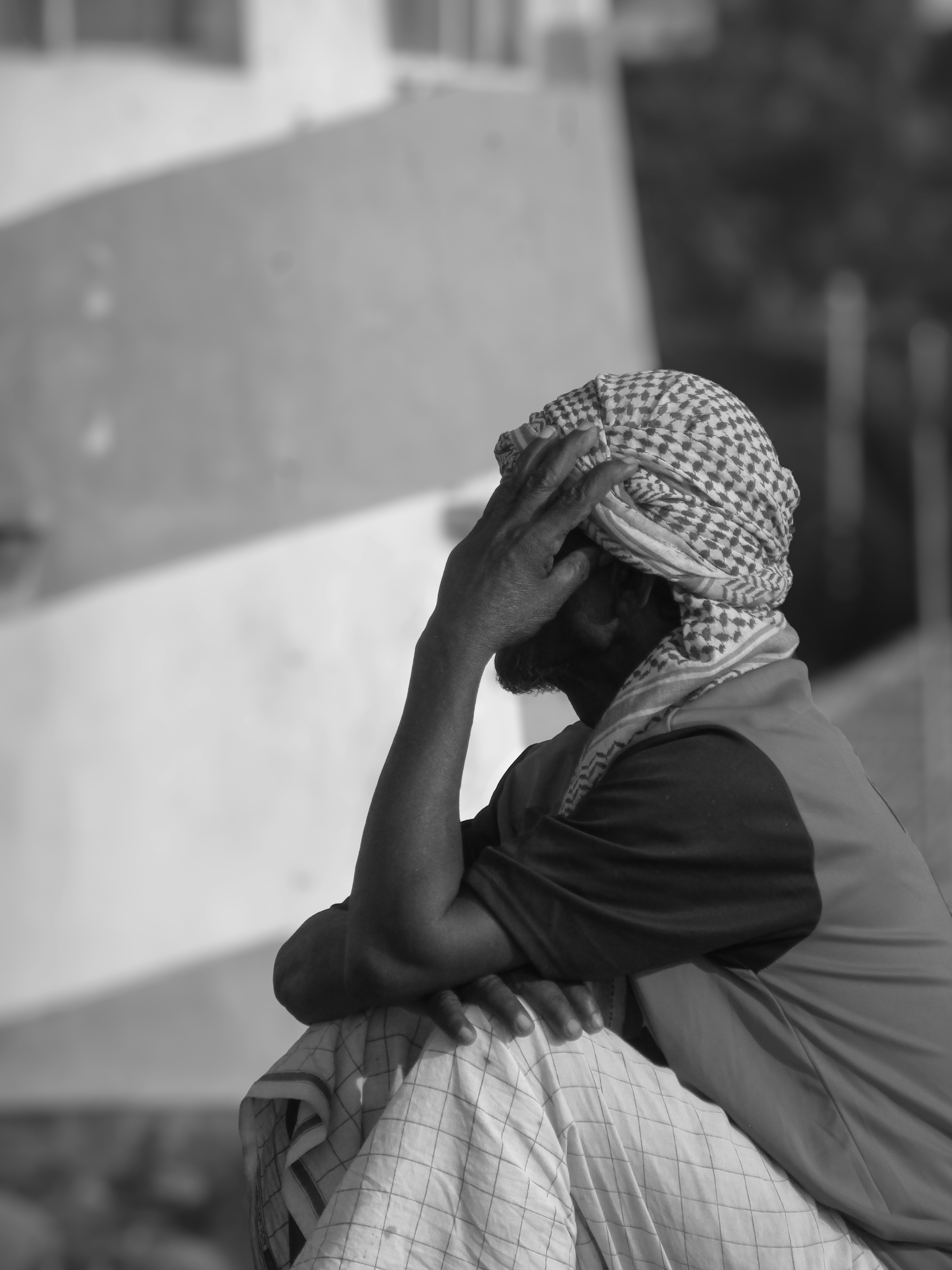 Man in turban resting head on hand outdoors.