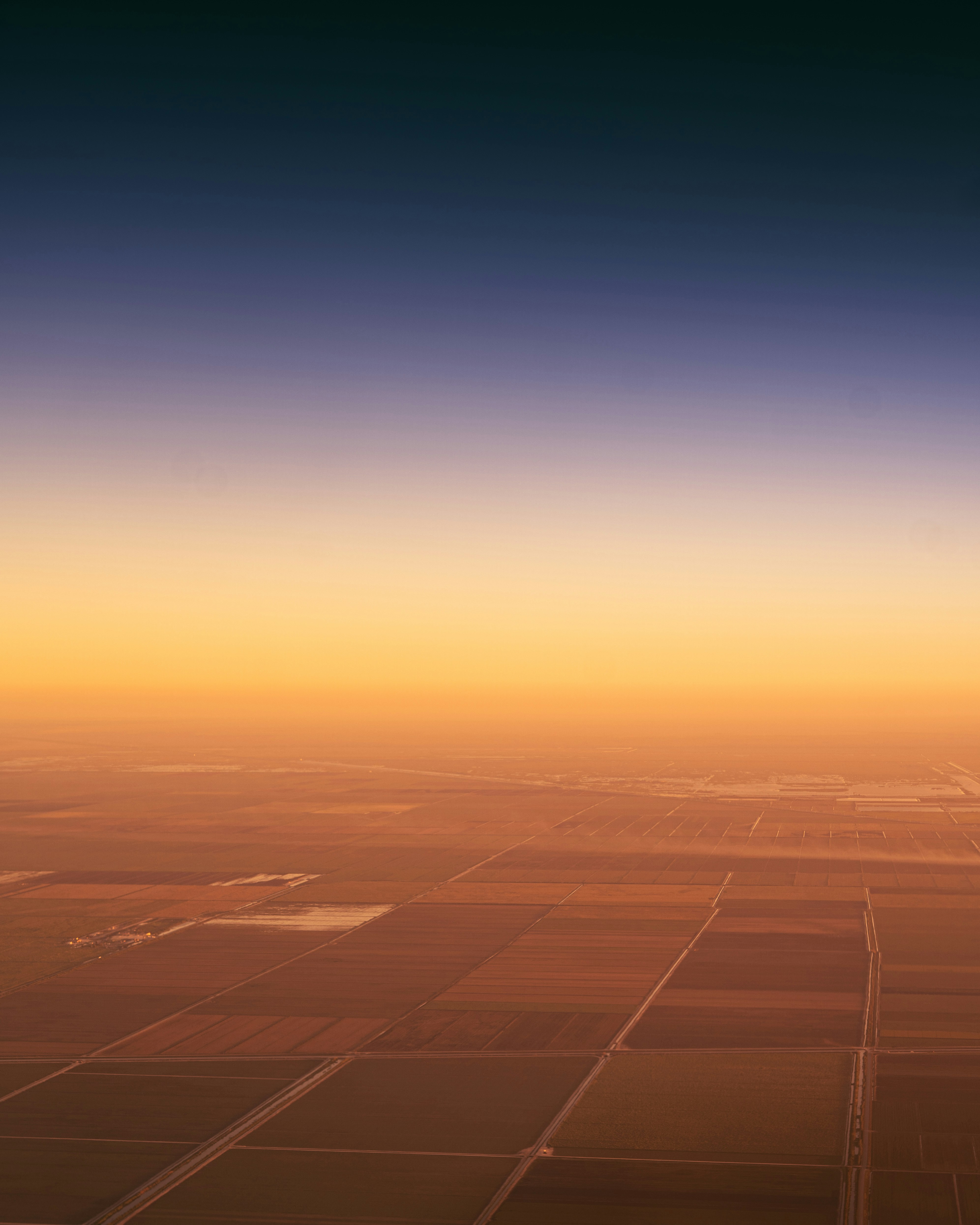 Aerial view of farmland at sunset with gradient sky.
