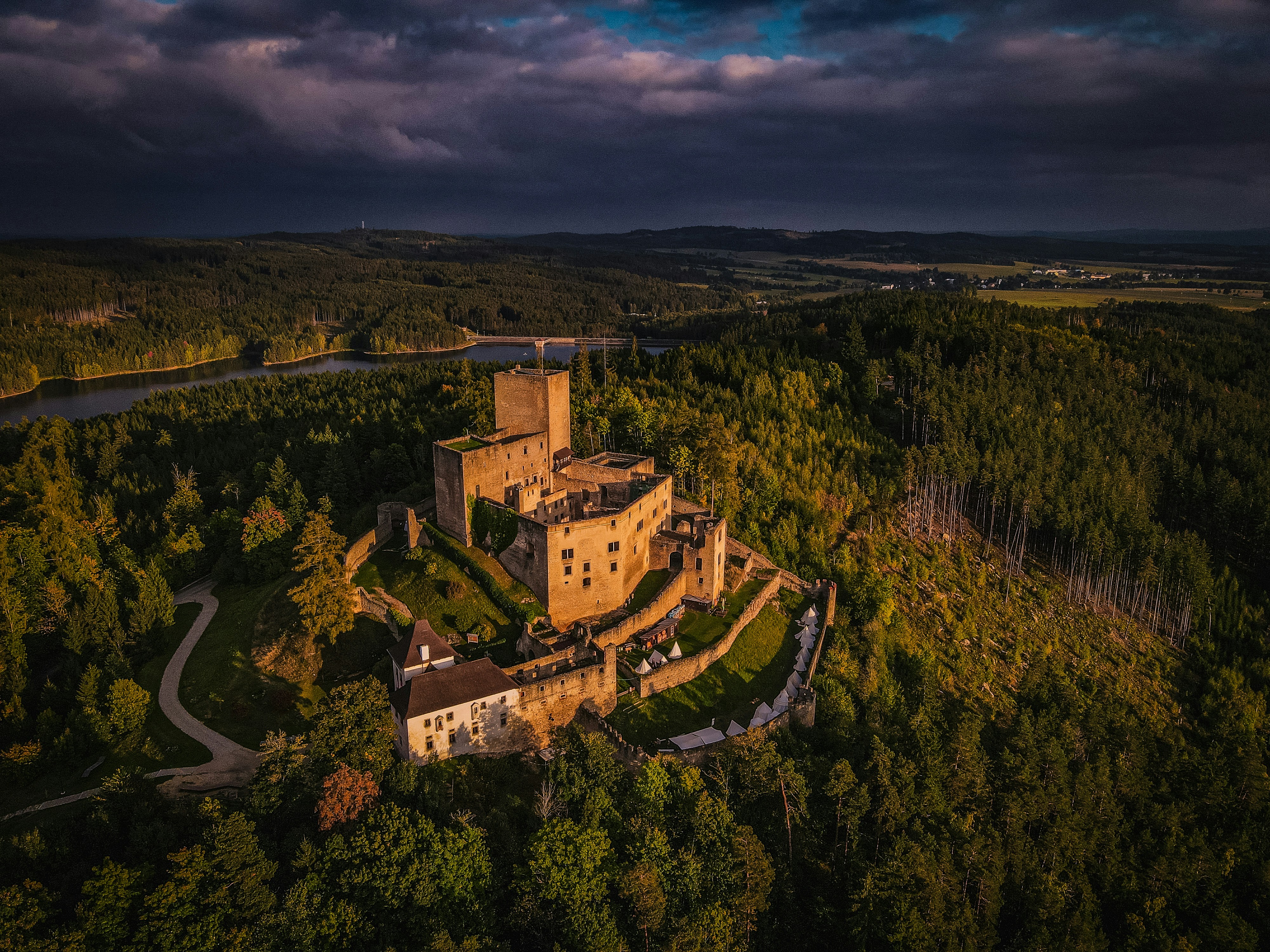 Ancient castle perched on a forested hill at sunset.