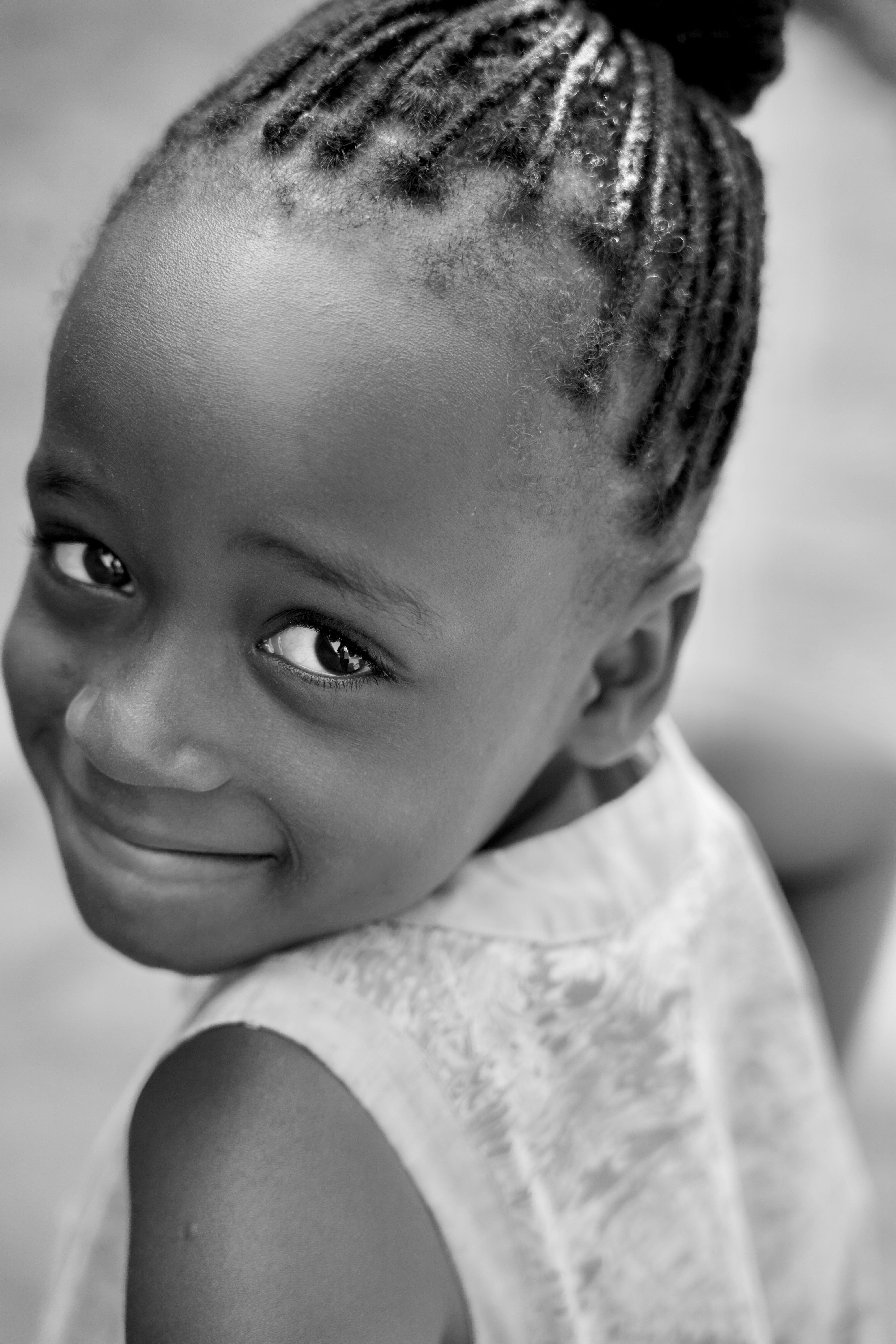A young girl with braided hair smiles coyly.