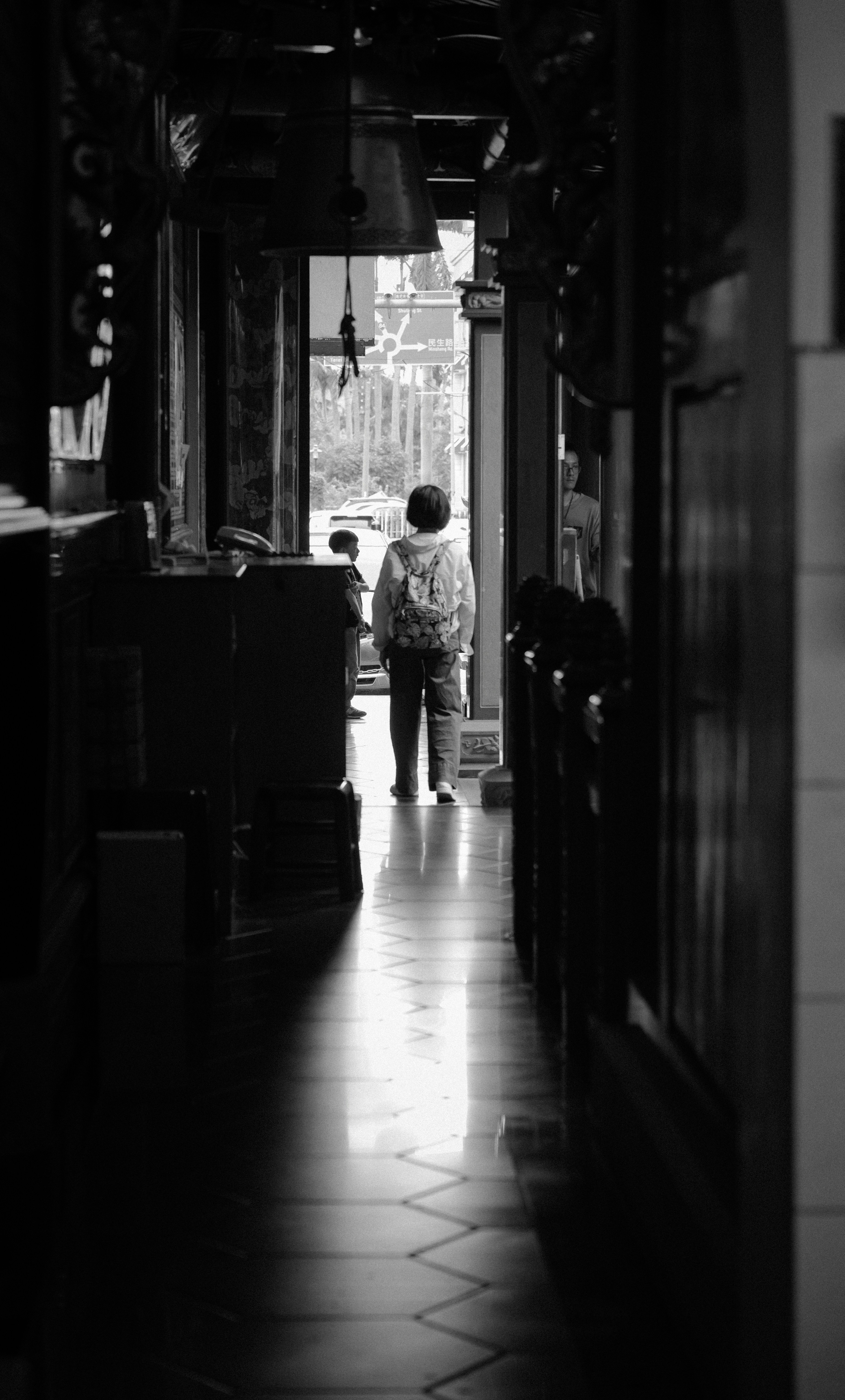 Child stands in a dimly lit hallway looking outside.