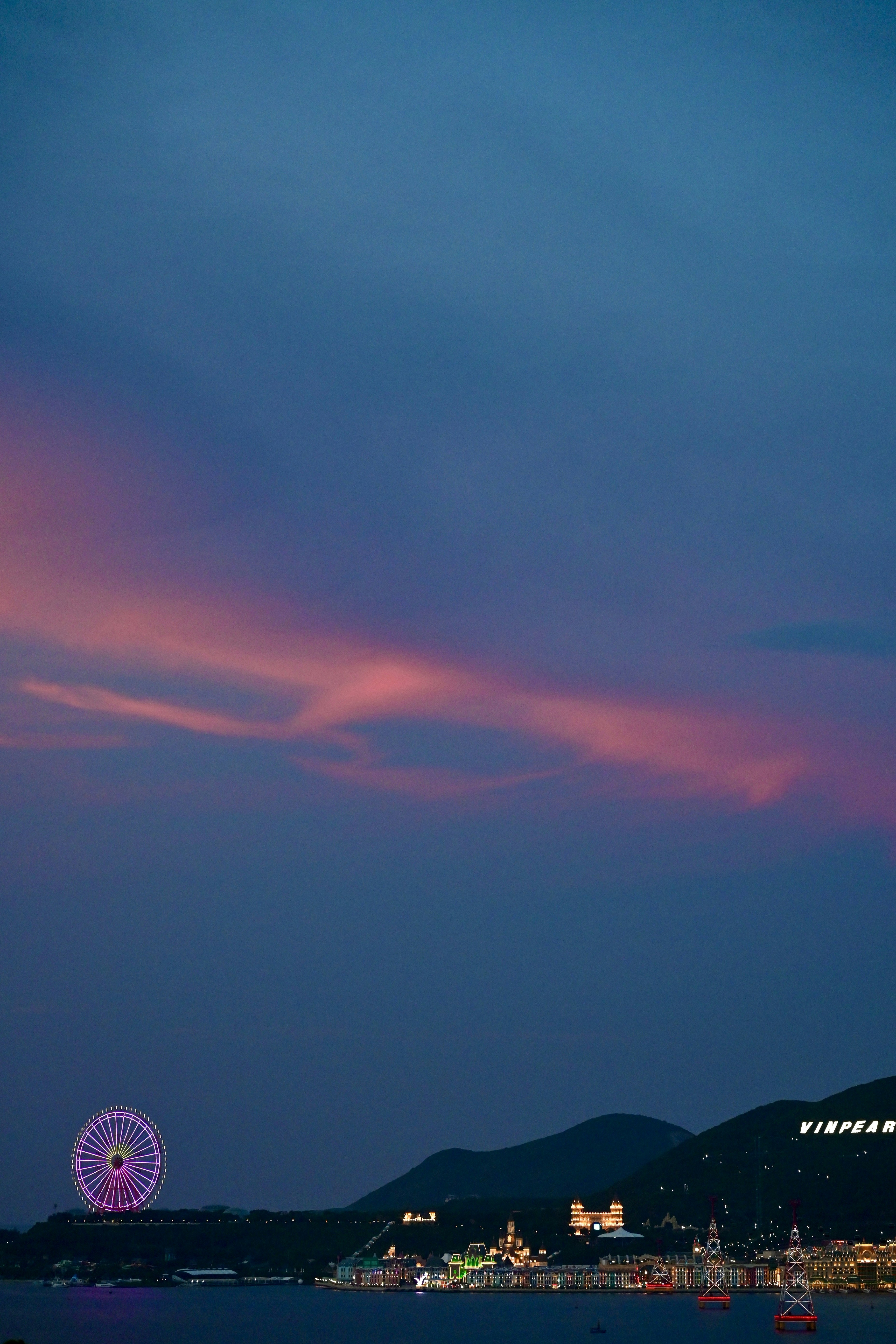 Ferris wheel and city lights at dusk with colorful sky