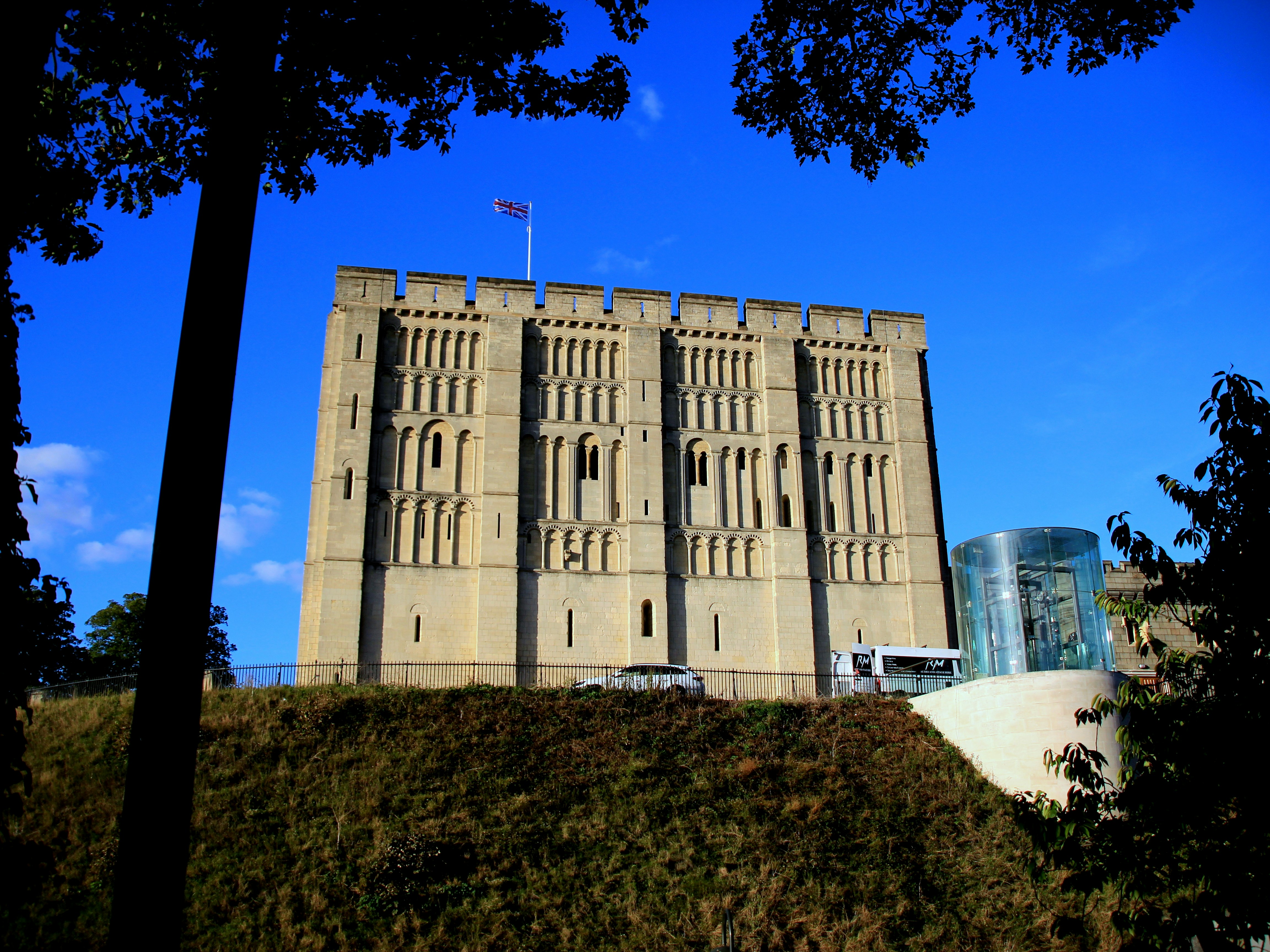 Stone castle structure on a grassy hill under blue sky.