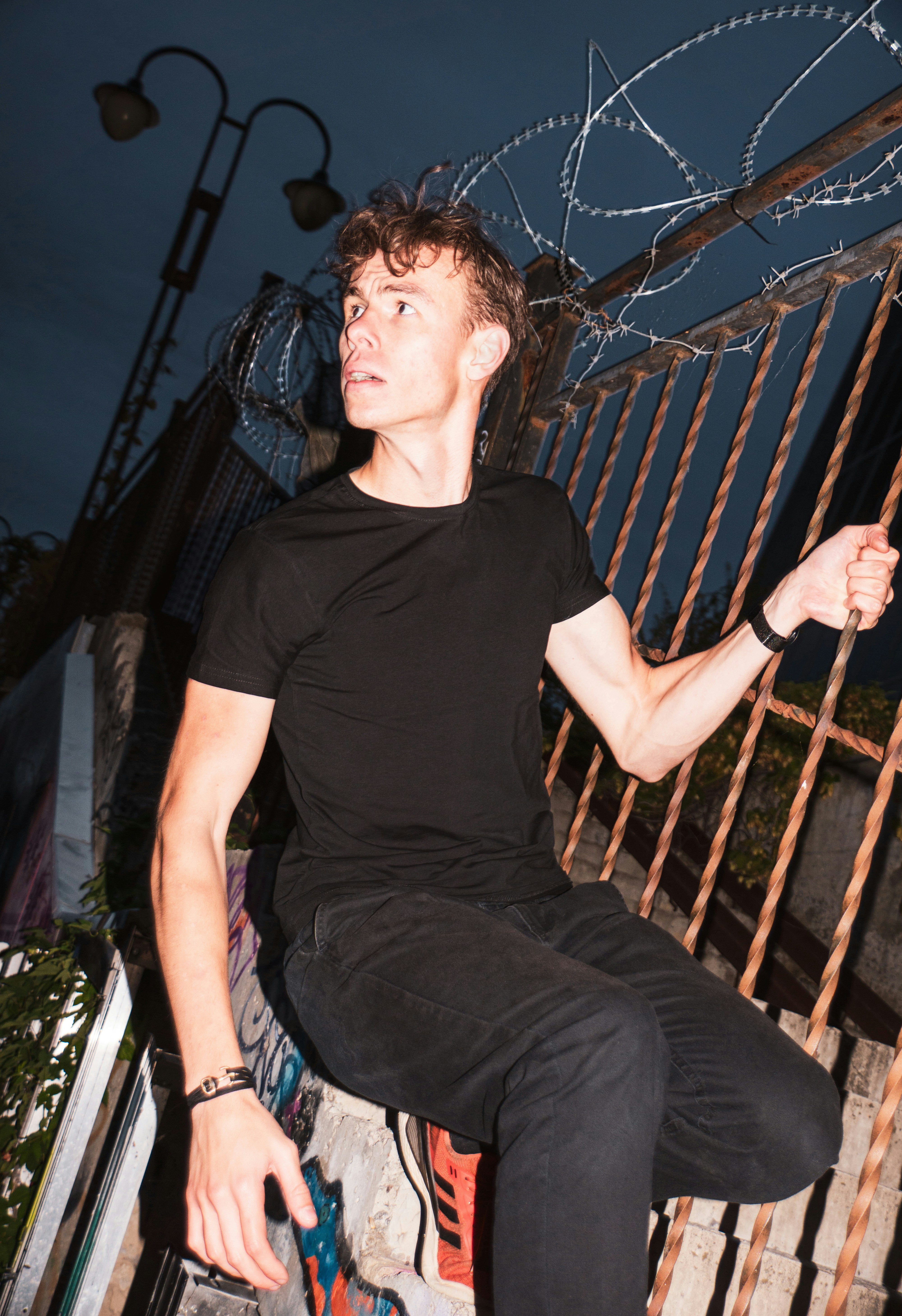 Young man in black shirt near barbed wire fence
