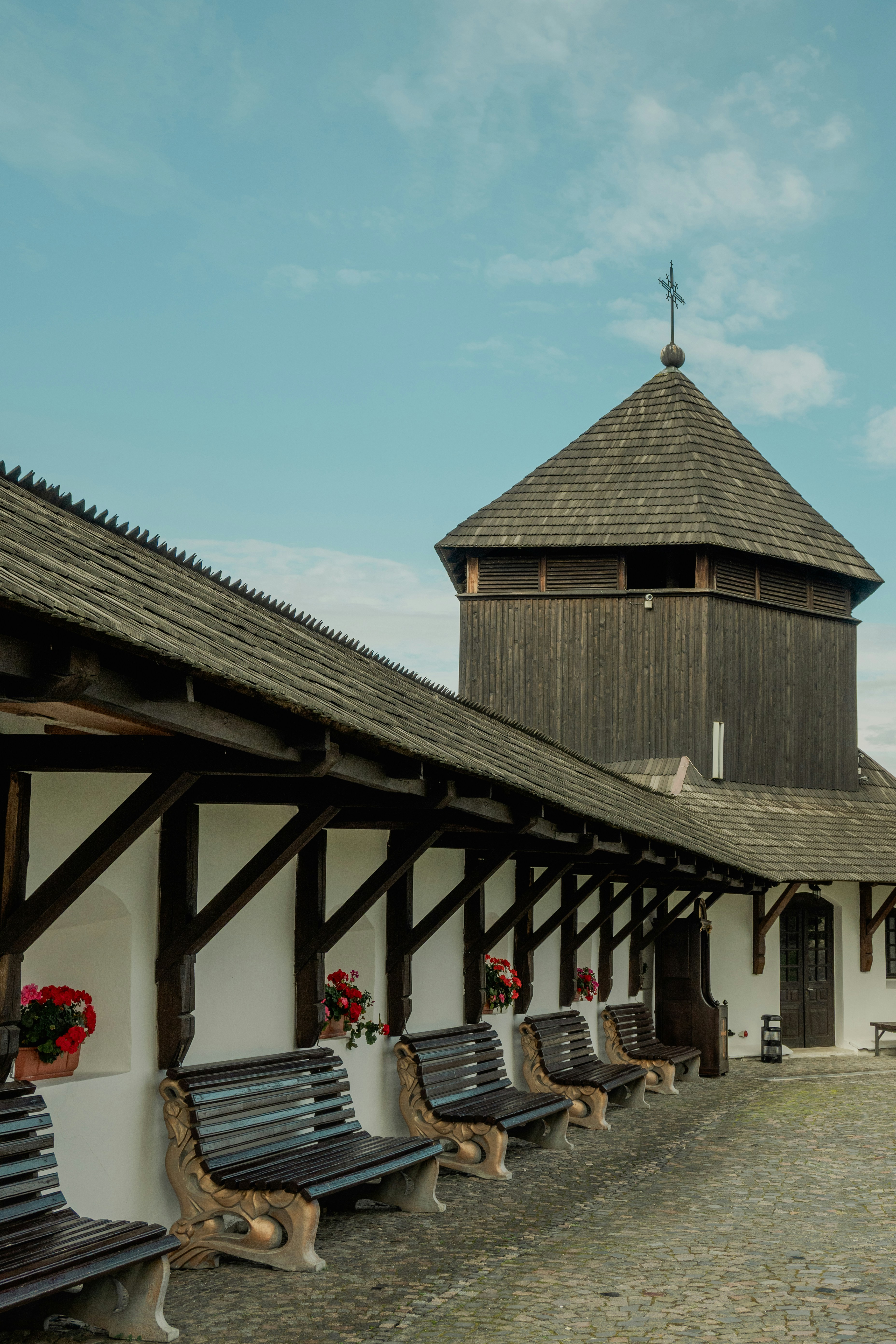 Wooden tower and benches beside white building