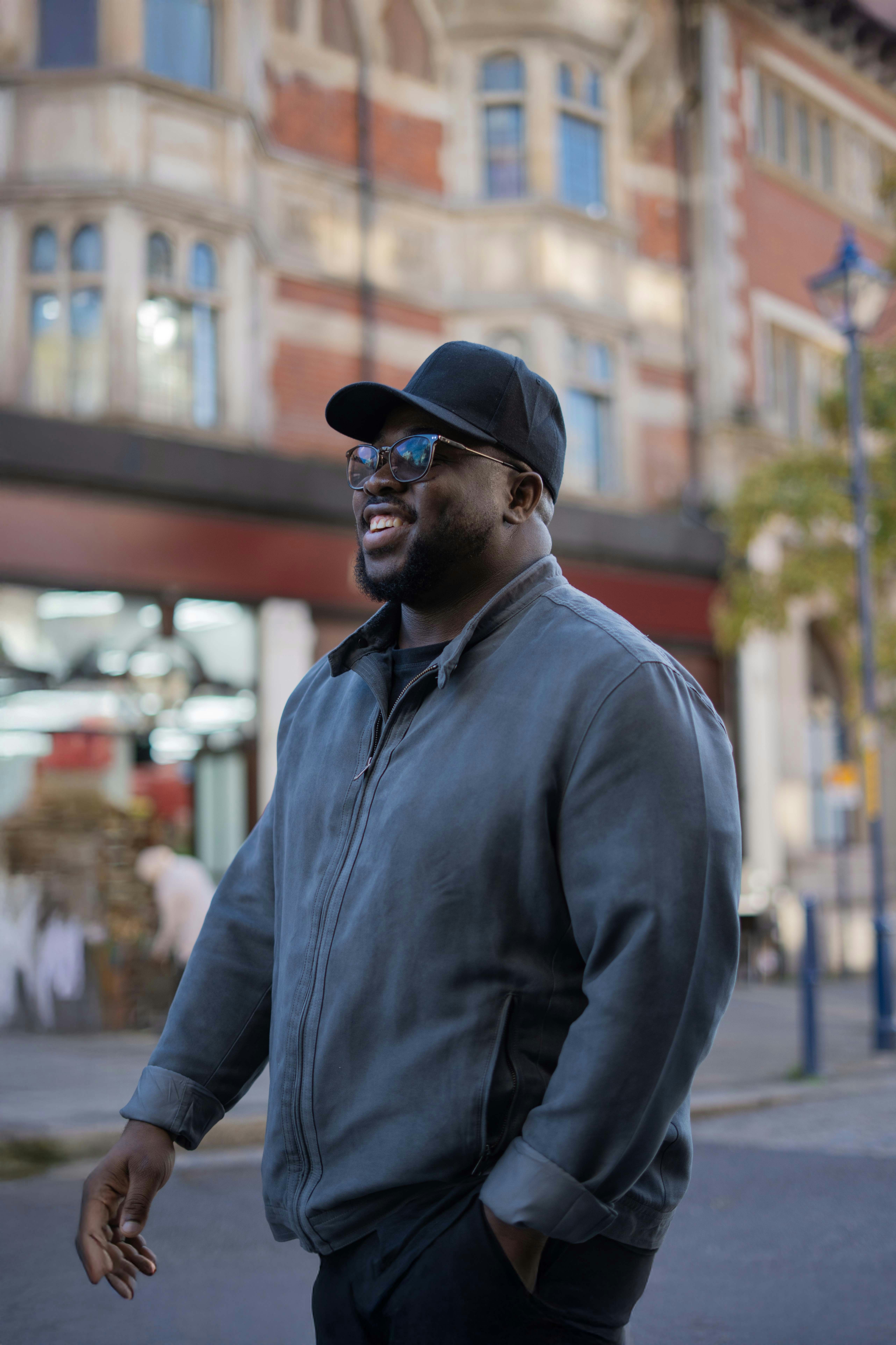 Man in a hat Walking | Man wearing a baseball cap and jacket walking outside.