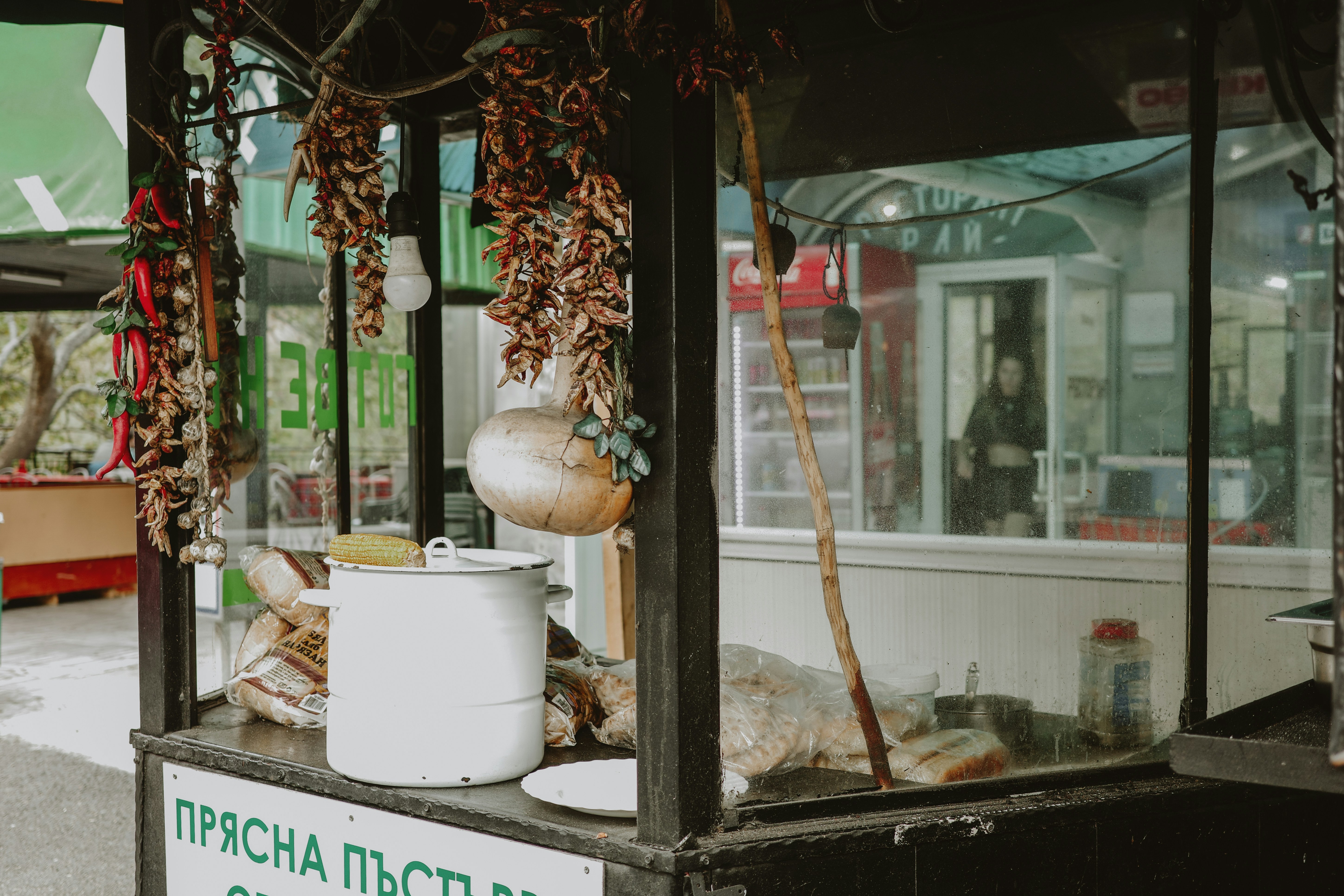 Dried chili peppers hang above a food stall display.