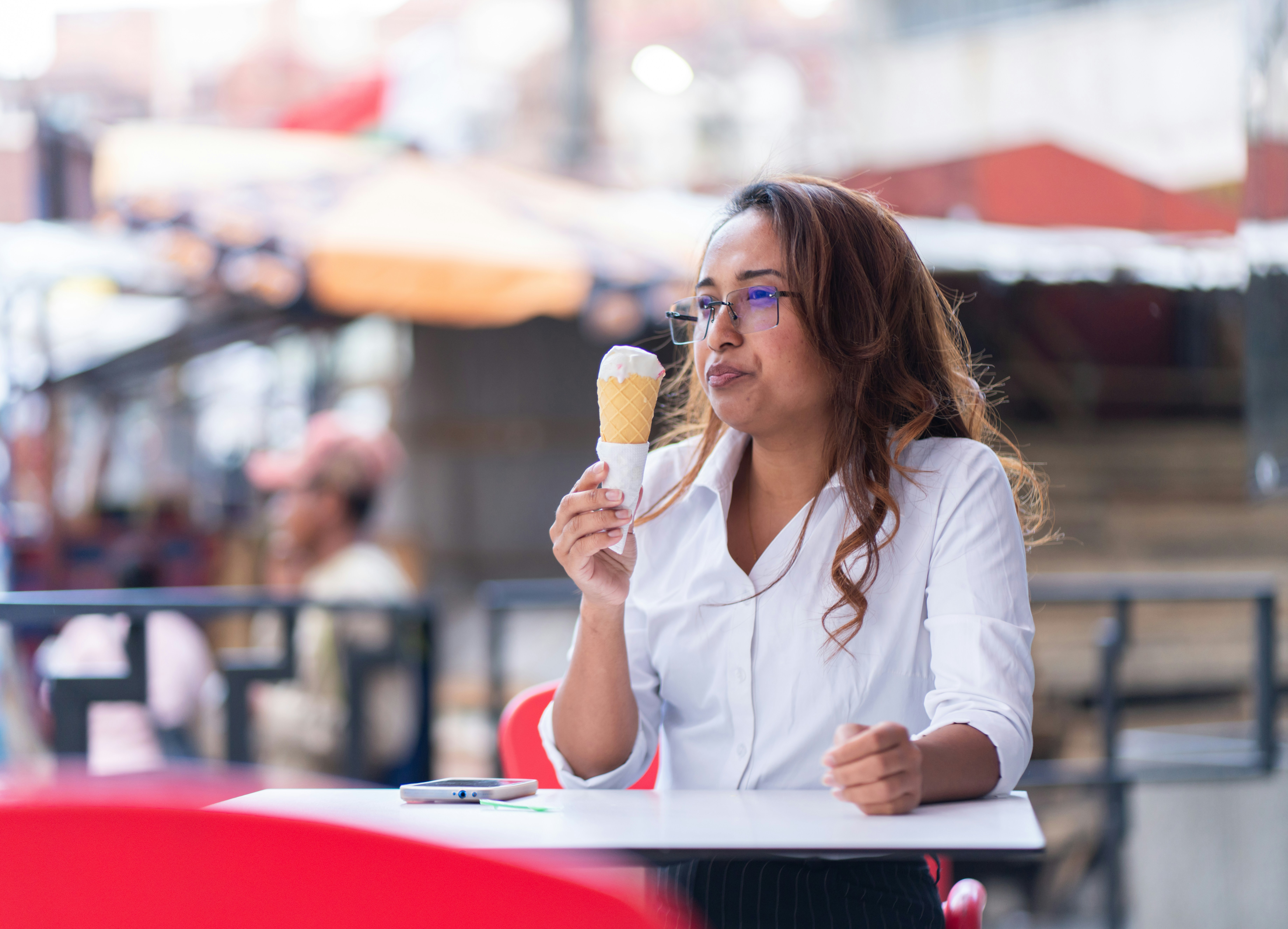 Woman eating an ice cream cone at a table
