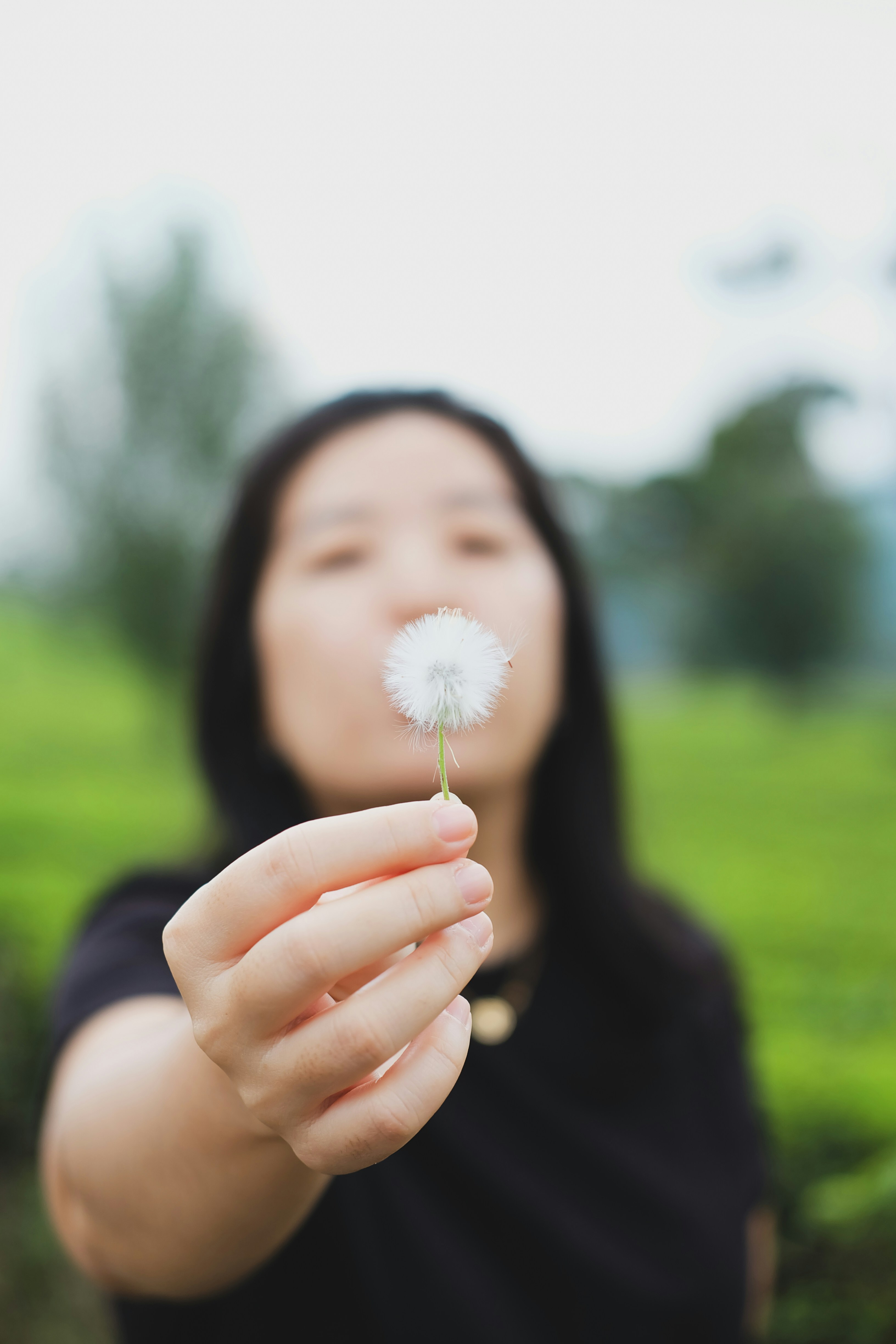 Woman holding a dandelion puffball outdoors