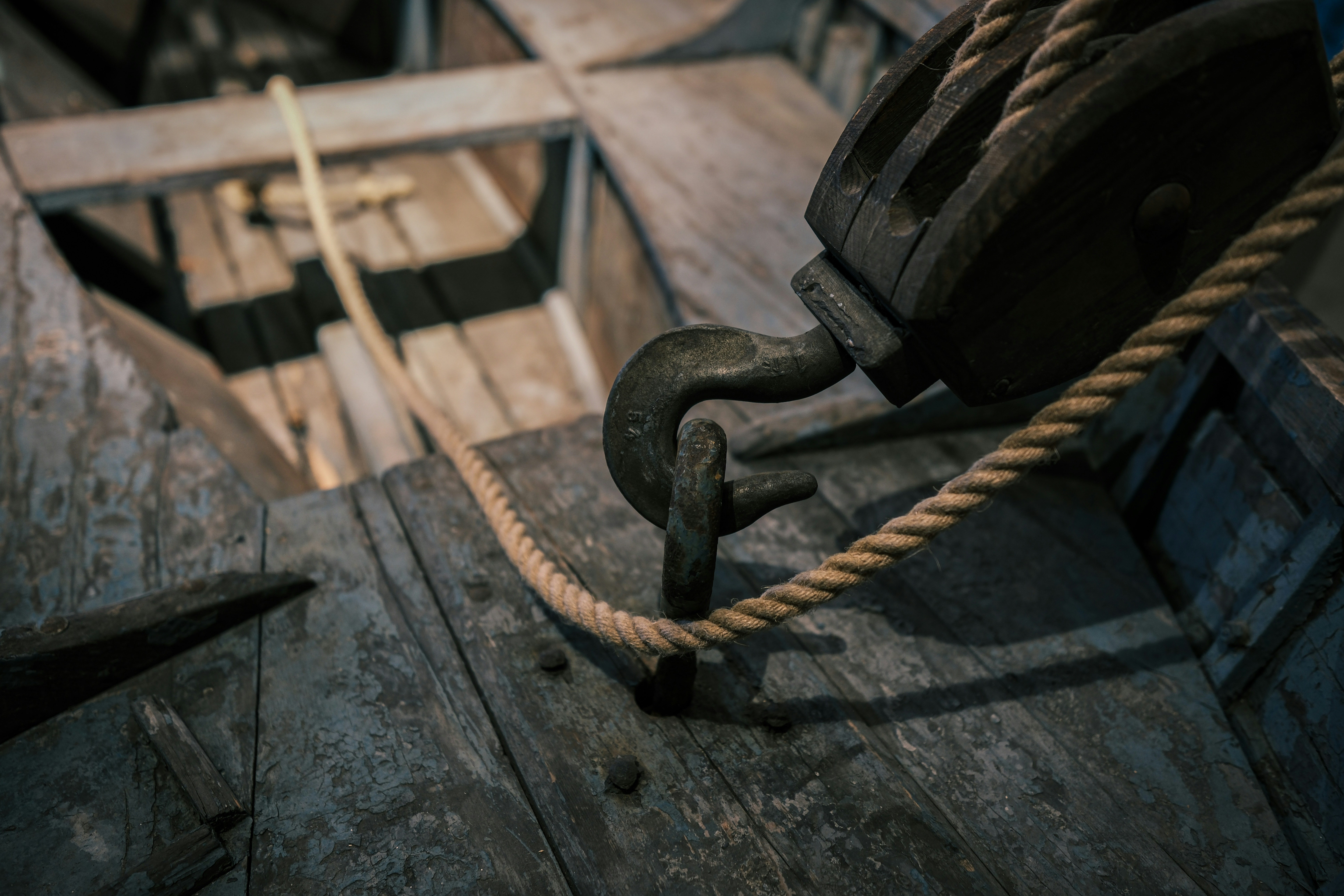 Close-up of a weathered pulley system on a wooden boat, showcasing the intricate details of maritime craftsmanship.