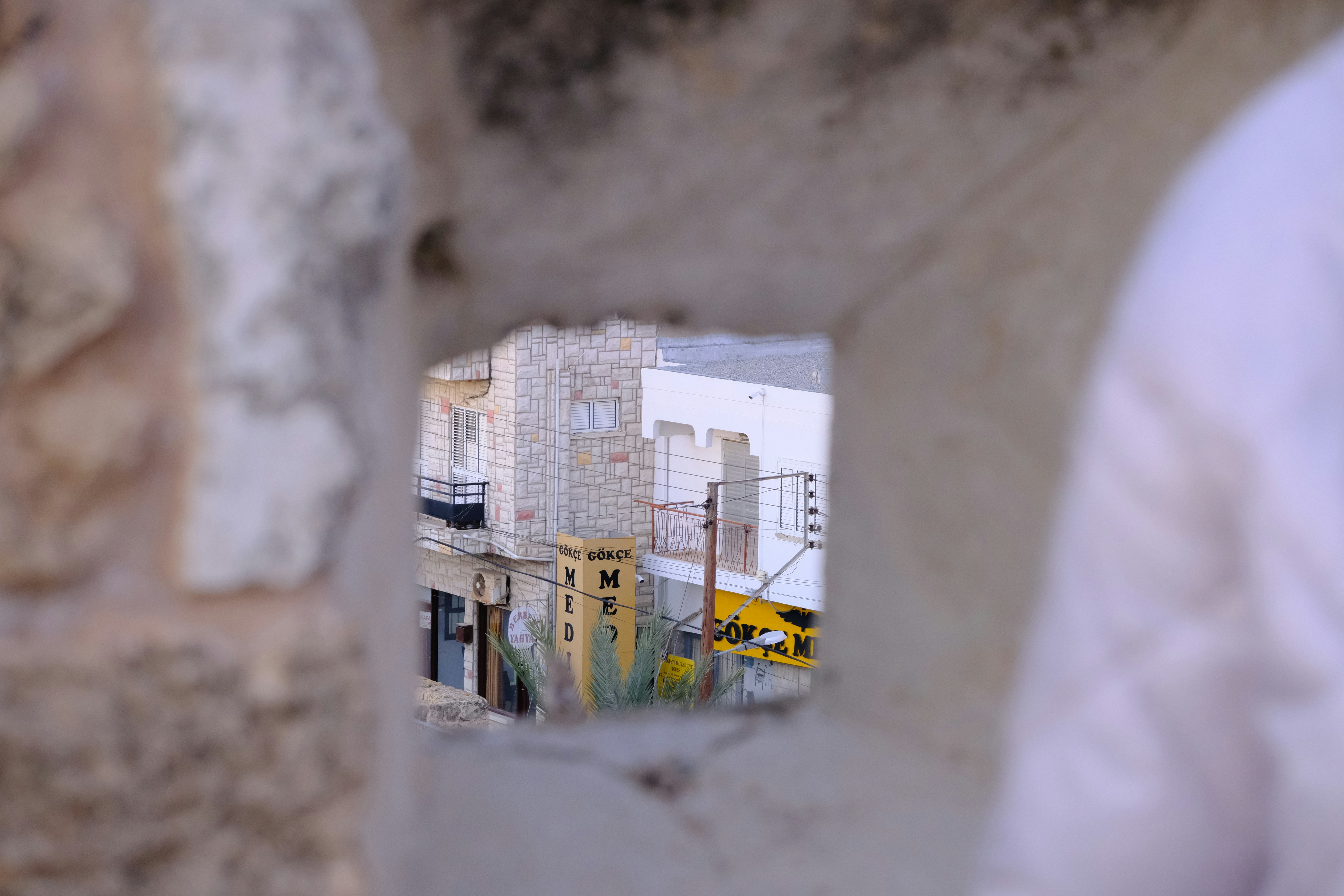 A glimpse through a stone opening reveals vibrant street art and architecture, showcasing the blend of history and modernity.