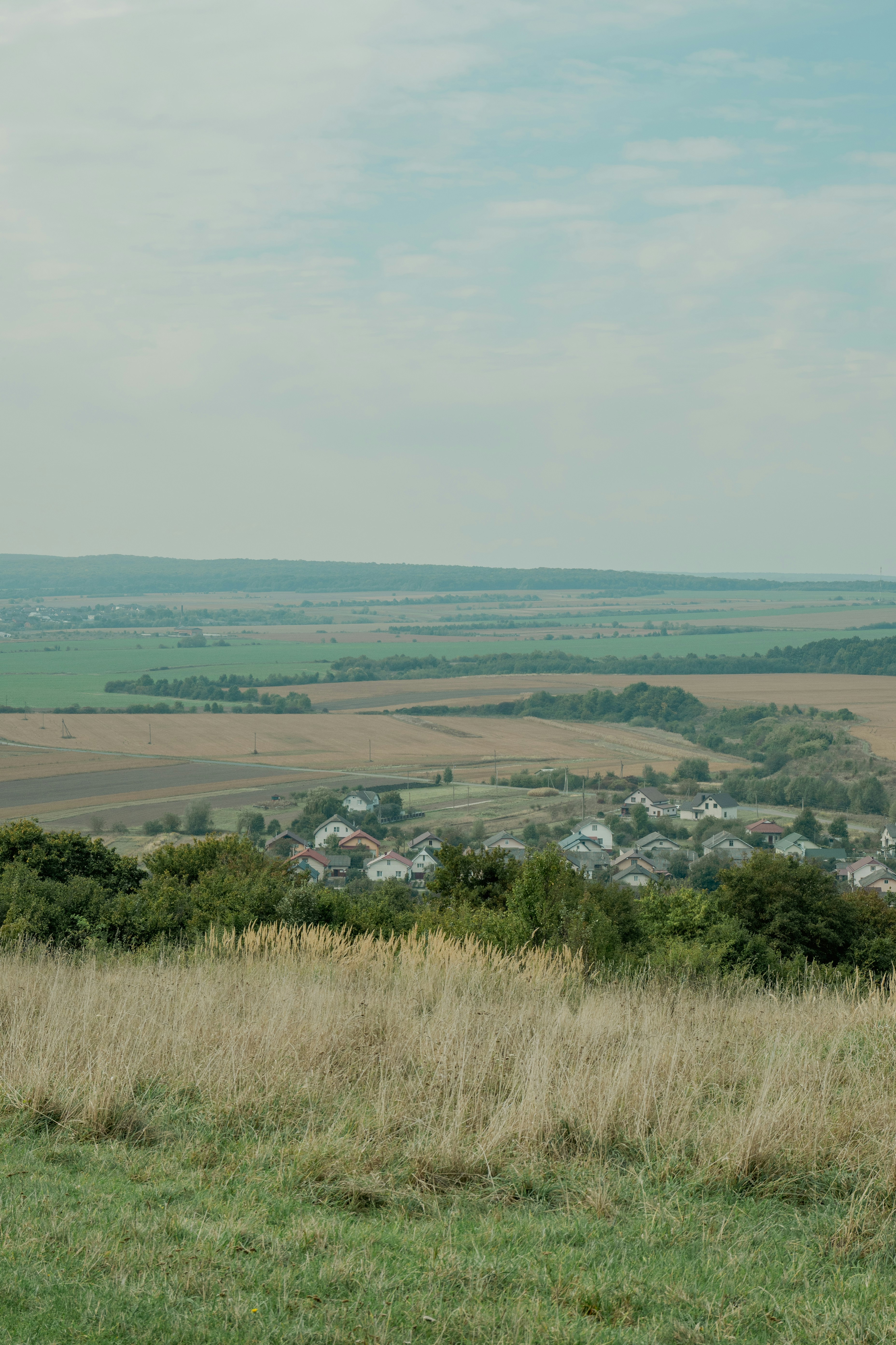 Rolling hills with a small village and fields.